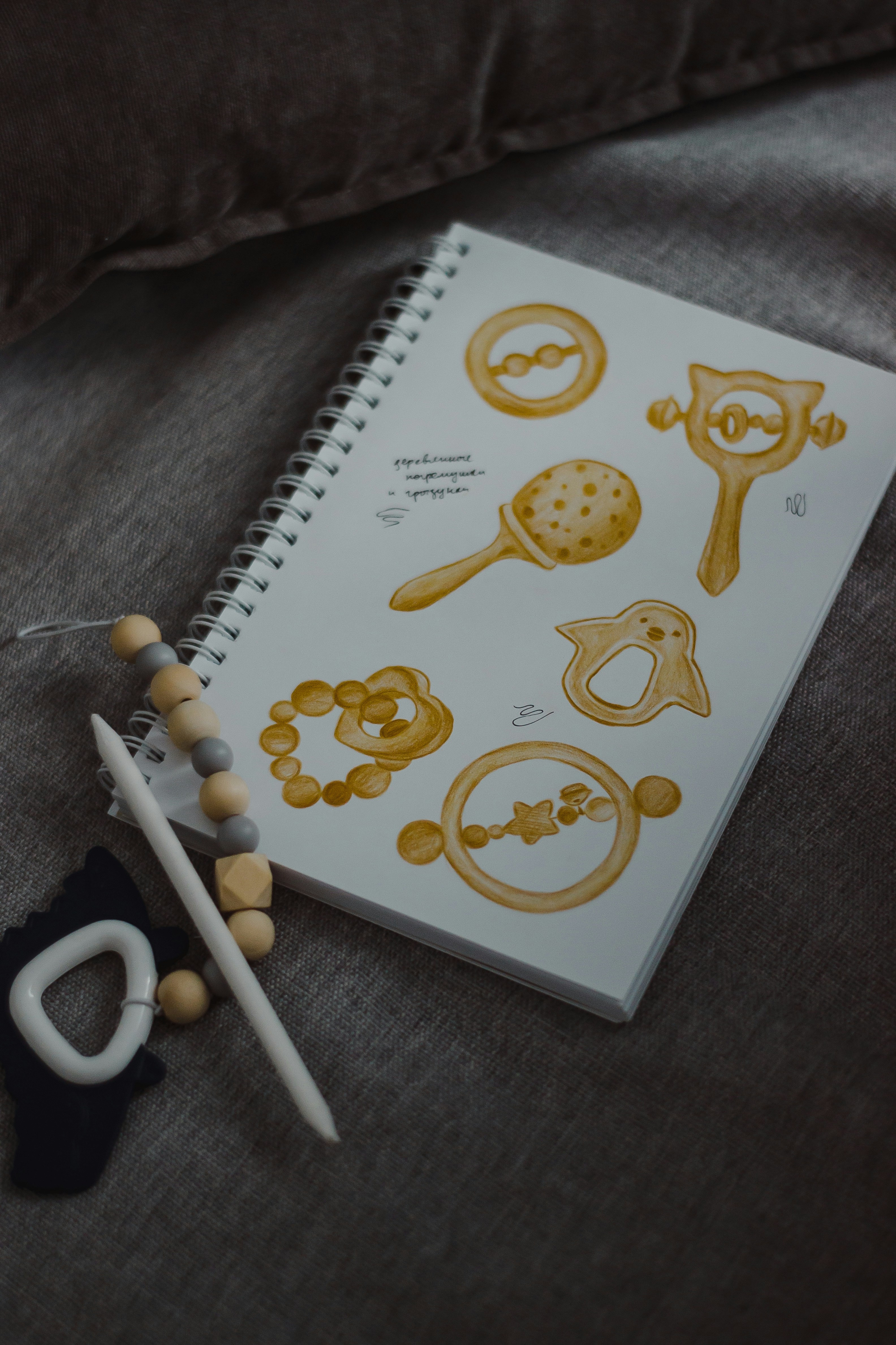 Golden sketches on a spiral notebook resting on a soft fabric backdrop