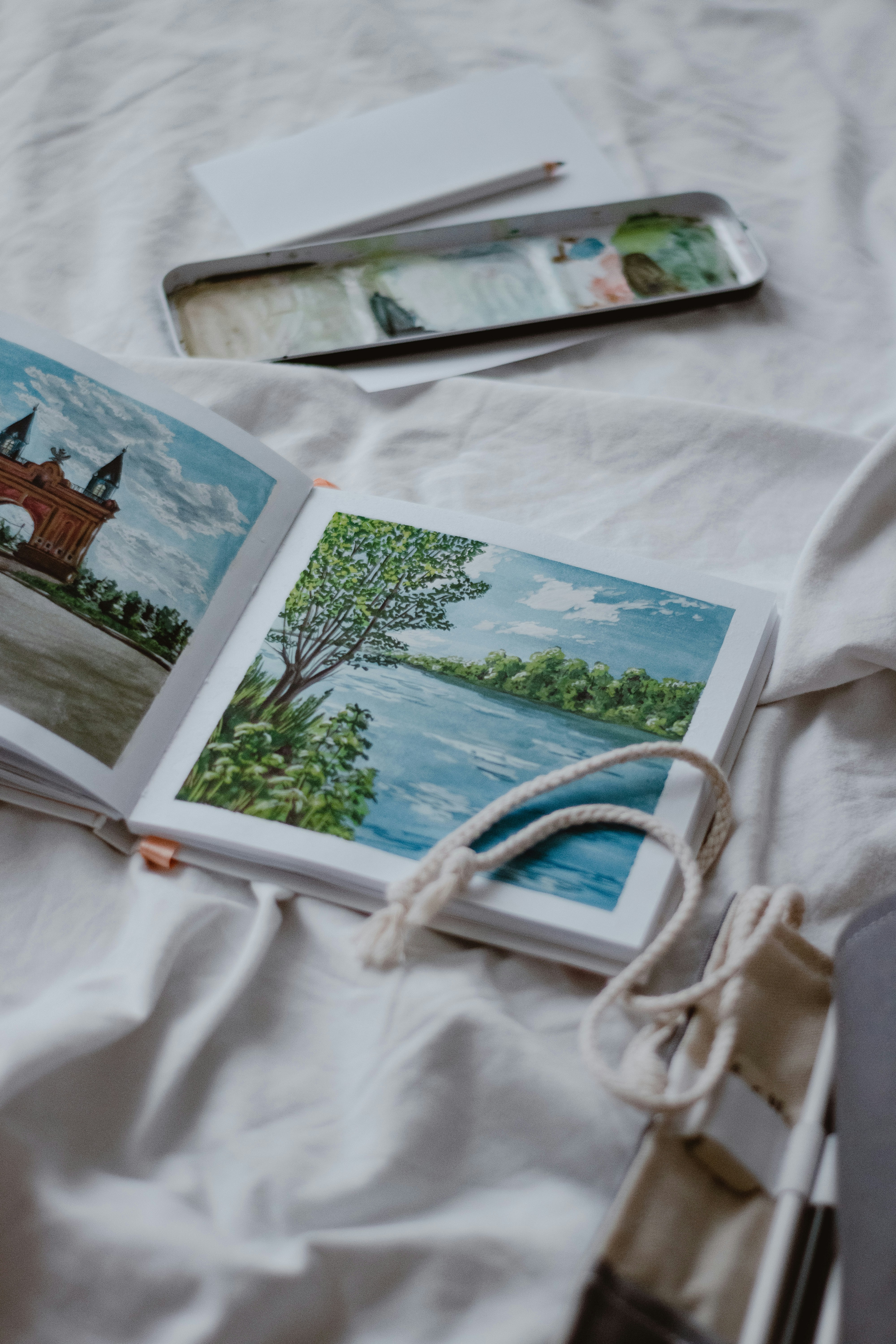 Art supplies and watercolor paintings on a bed. photo – Free Book Image ...