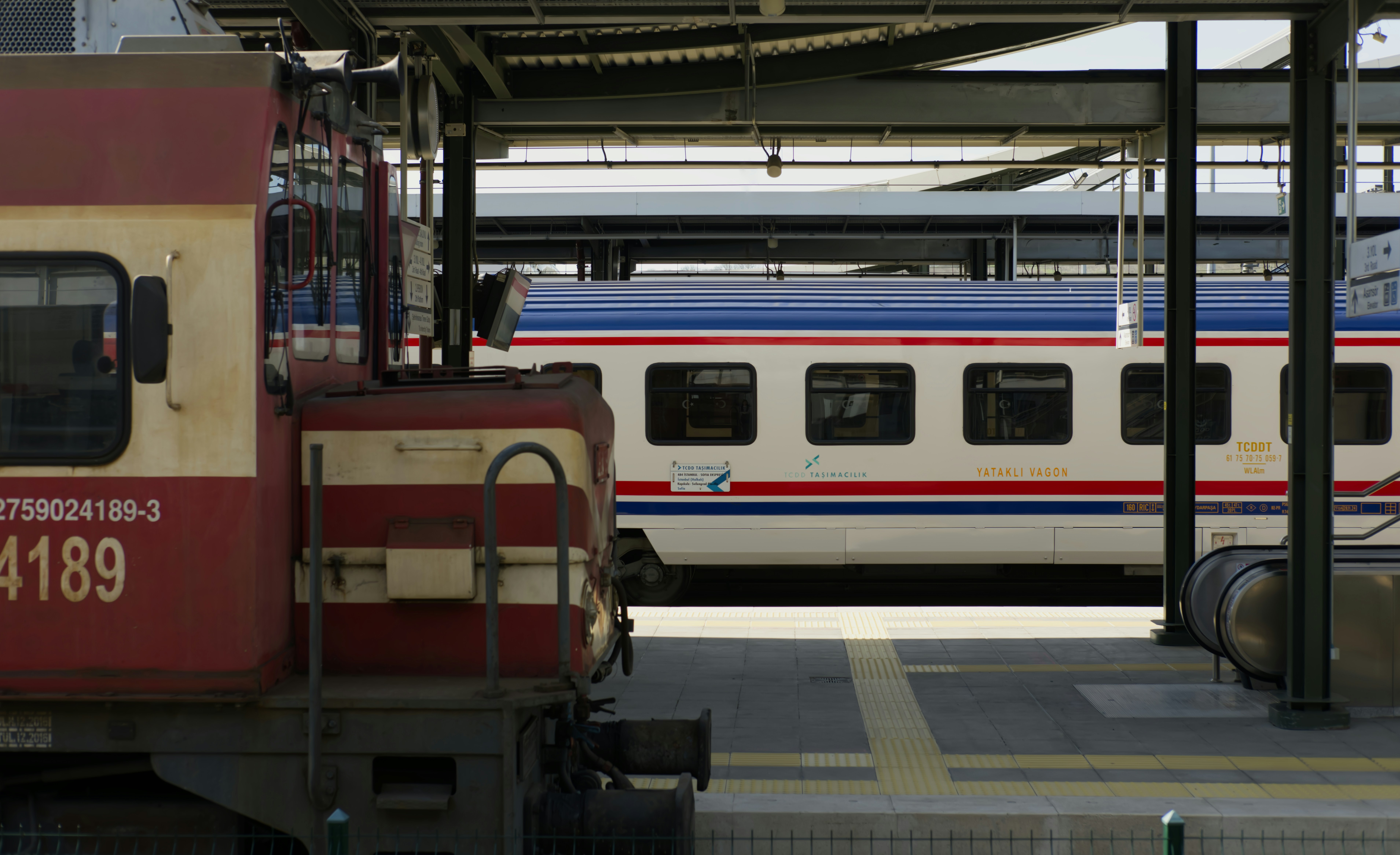 Platform Confluence: Red Locomotive Meets Striped Passenger Car