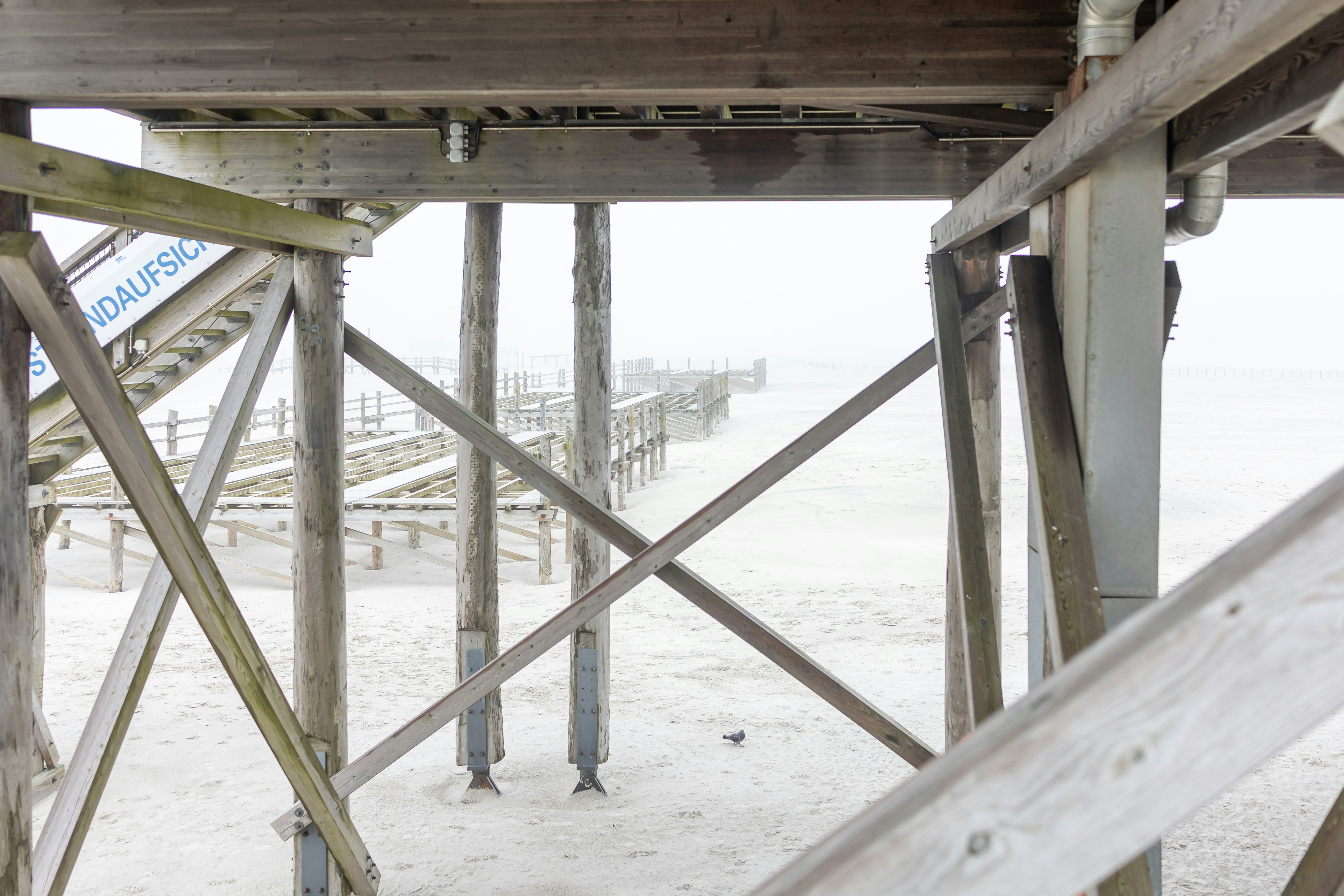 Under the Pier: Intersecting Beams Framing a Seaside Quiet