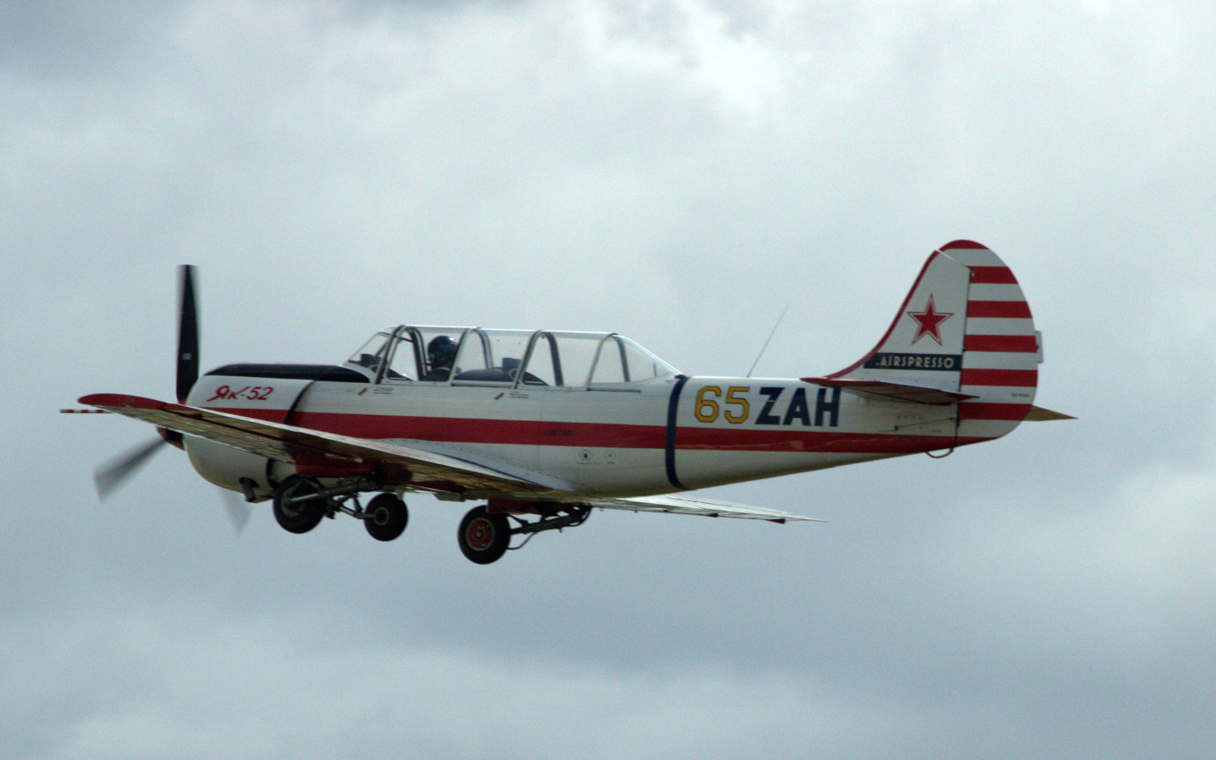 Red-and-white tandem trainer slicing through a cloud-streaked sky