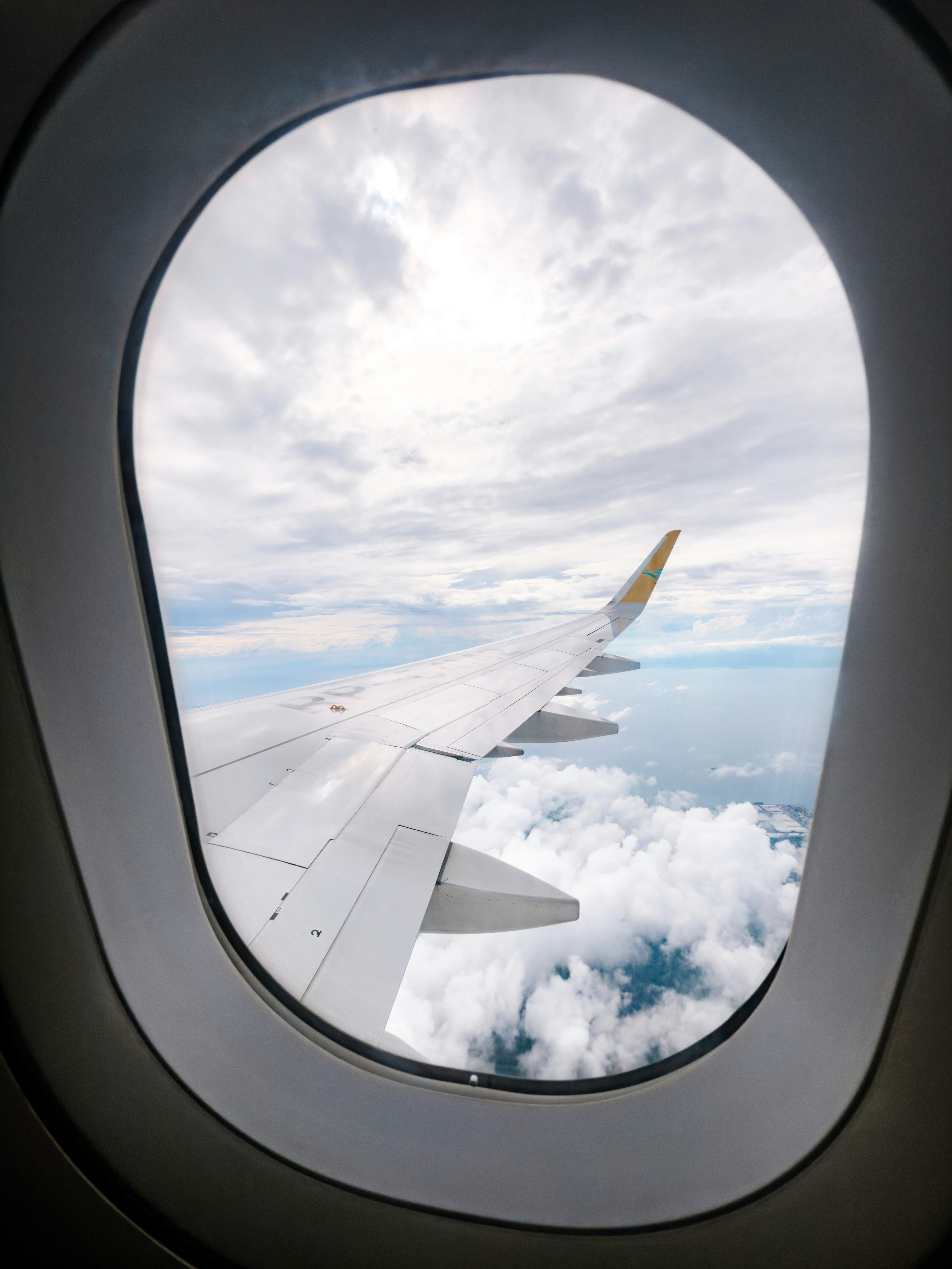 Wing Above the Clouds: A Silver Silhouette Through an Airplane Window