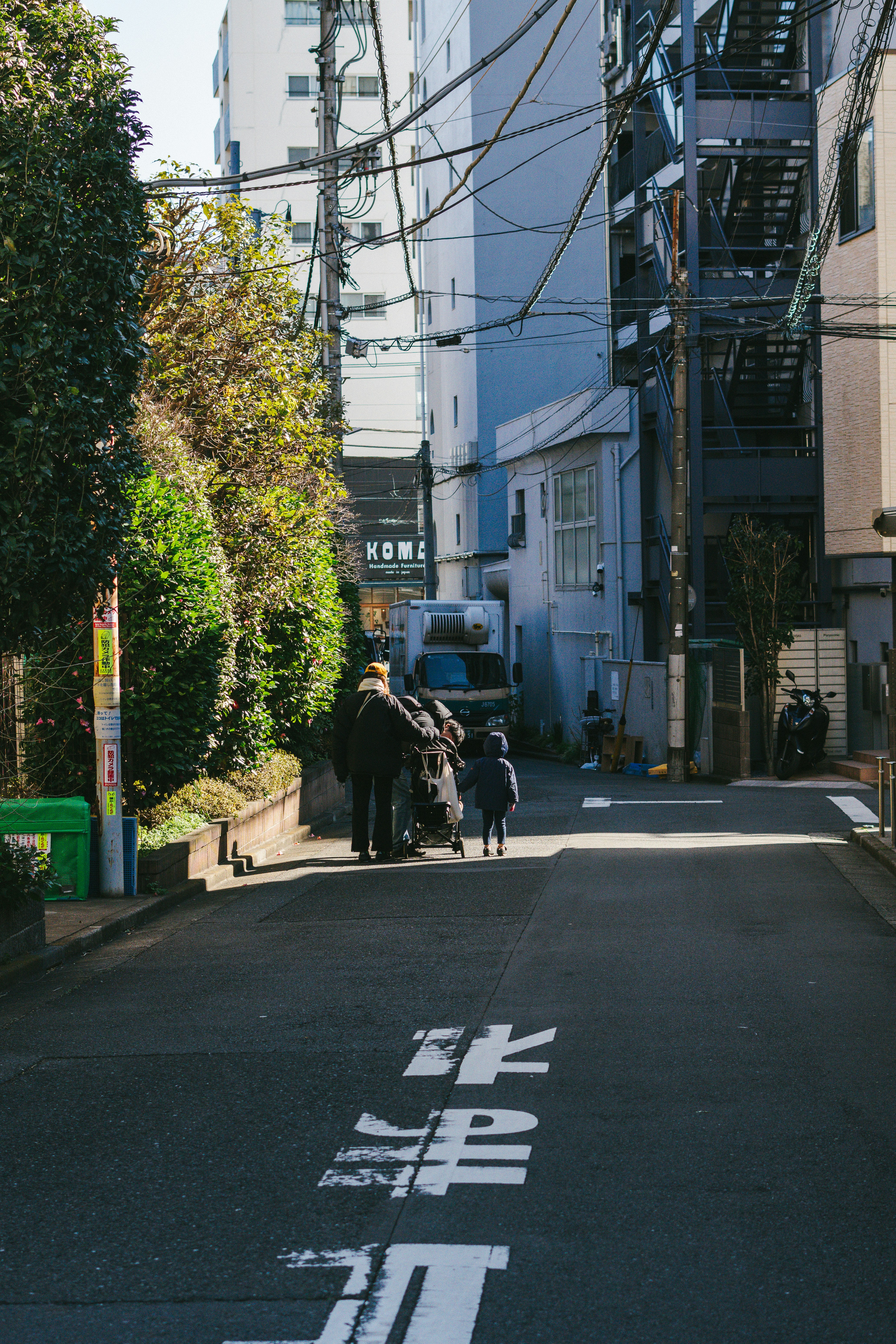 Alleyway Pause: A Family Walk Beneath a Web of Power Lines