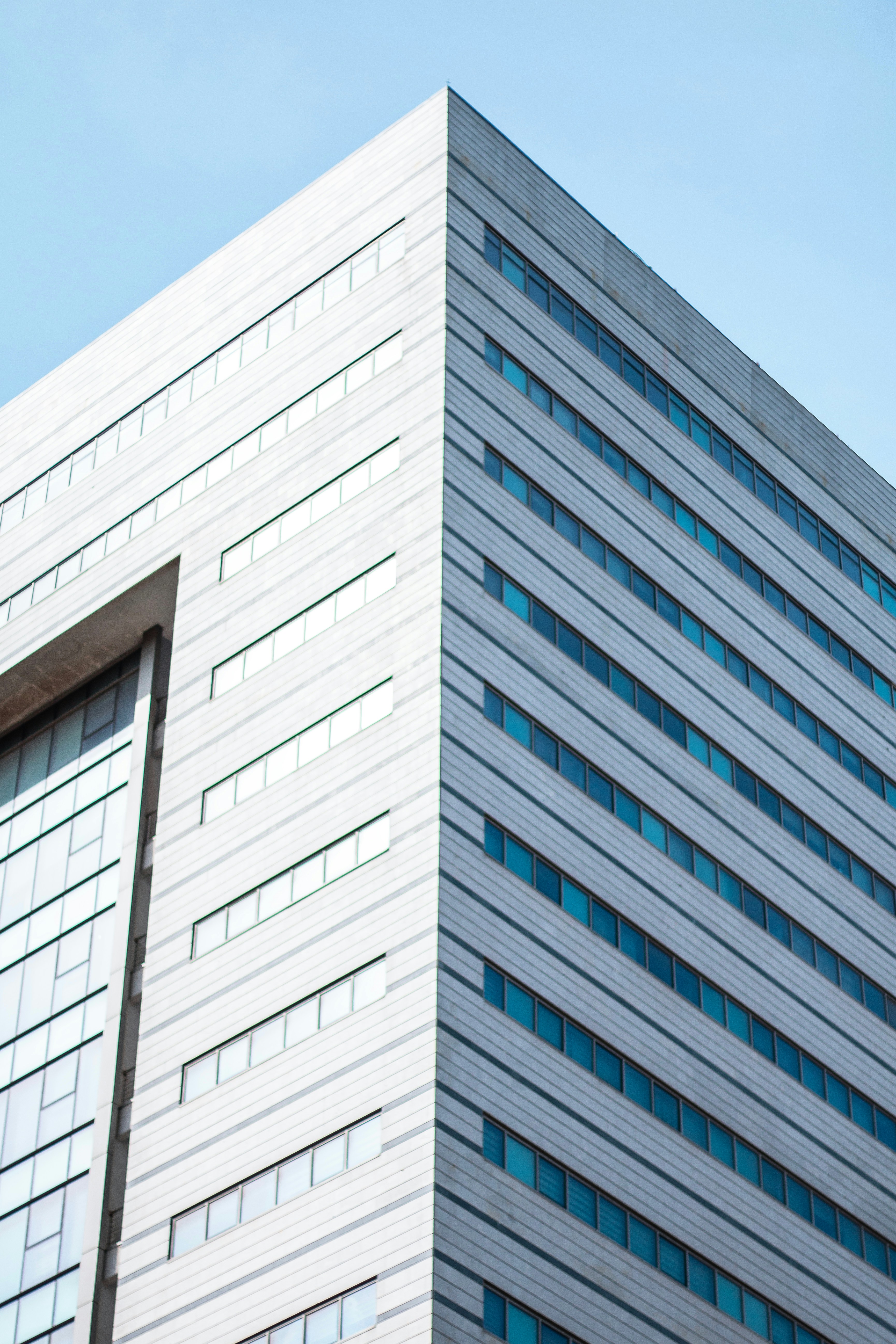 Modern high-rise building with sleek lines and reflective windows under a clear blue sky.