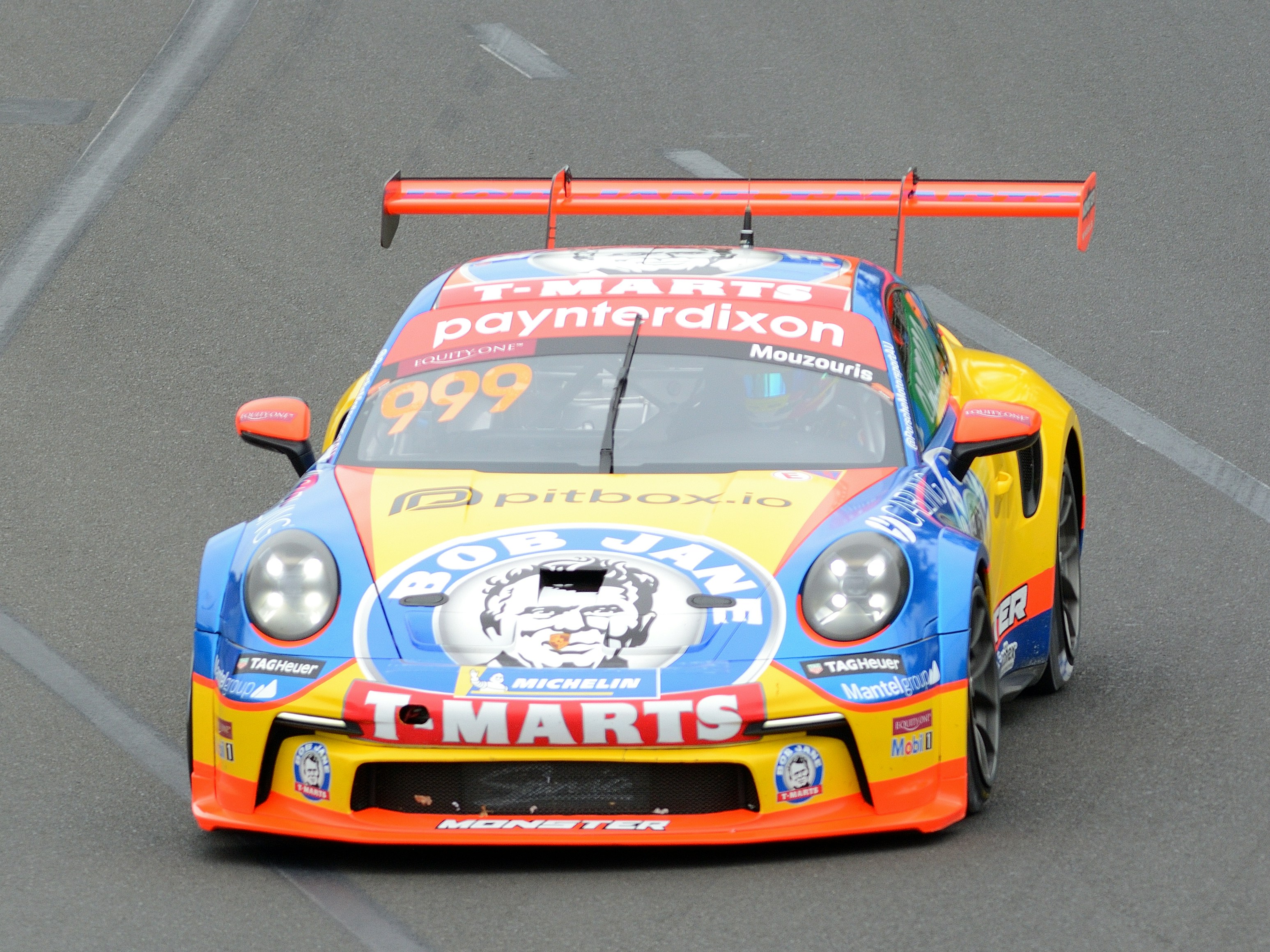 Colorful Porsche Carrera racing down a track with sponsor logos on its body.