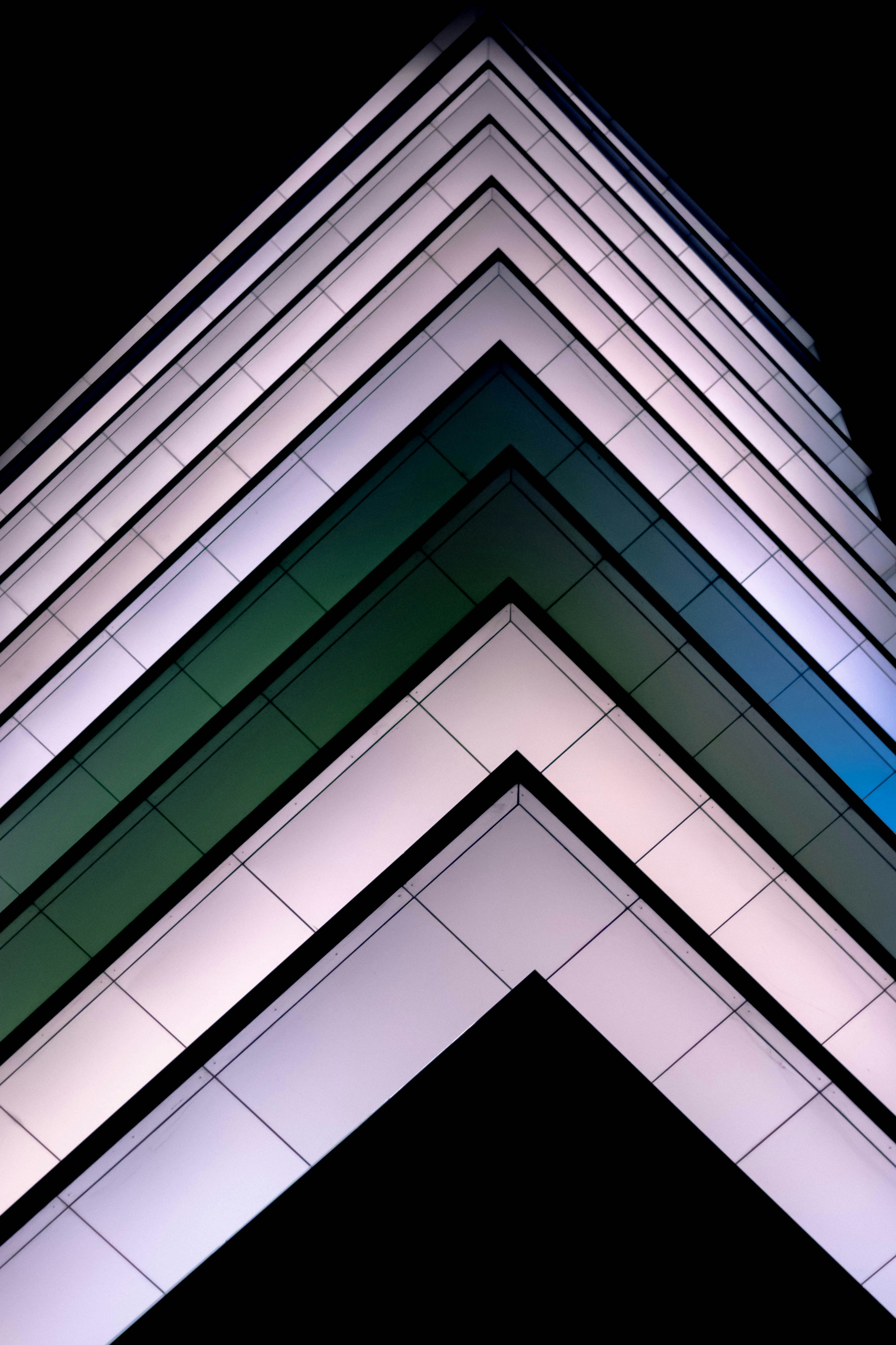 Geometric lines of a modern building facade illuminated against a dark sky.