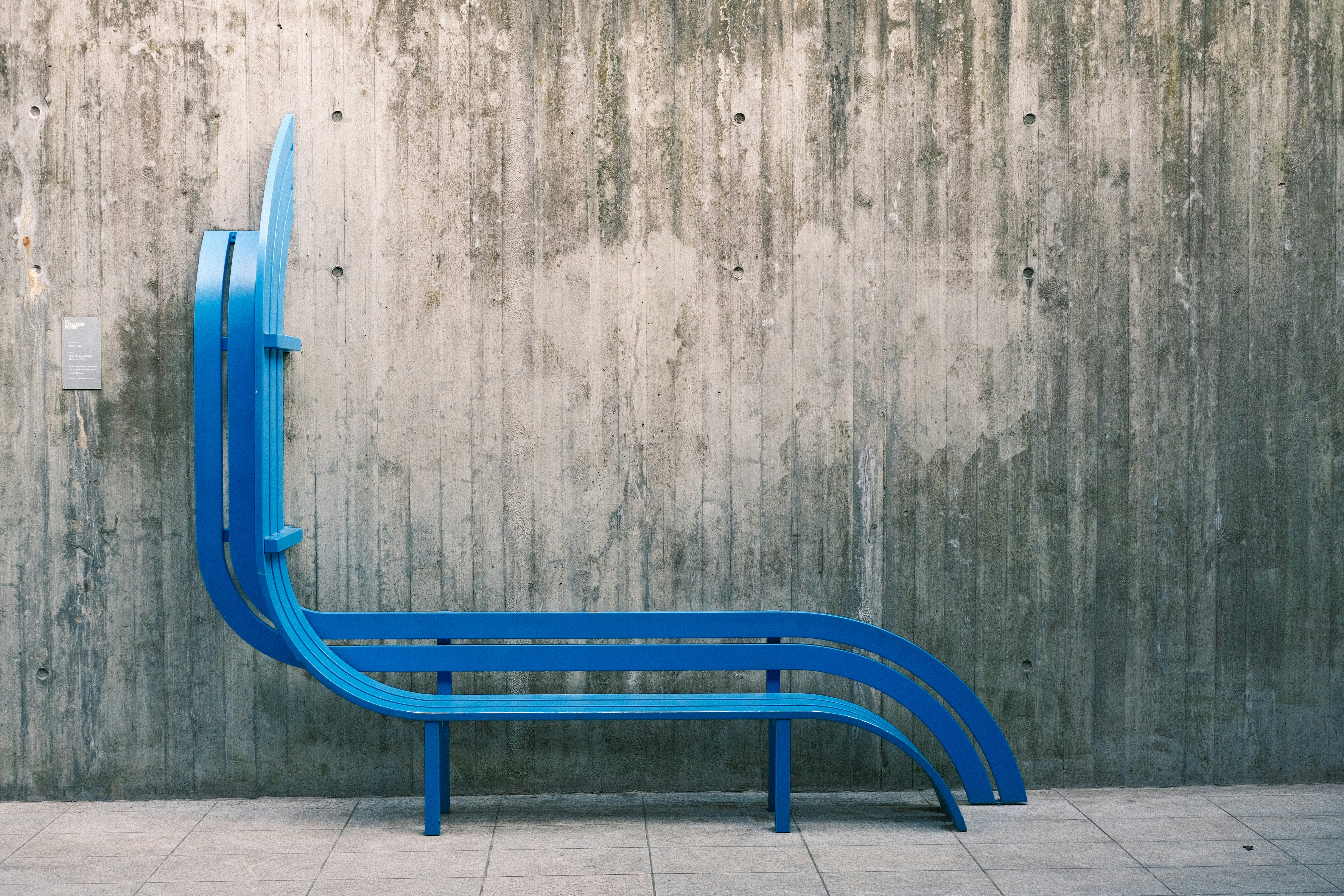 Electric Blue Arc: A Minimalist Bench Framed by Concrete Texture