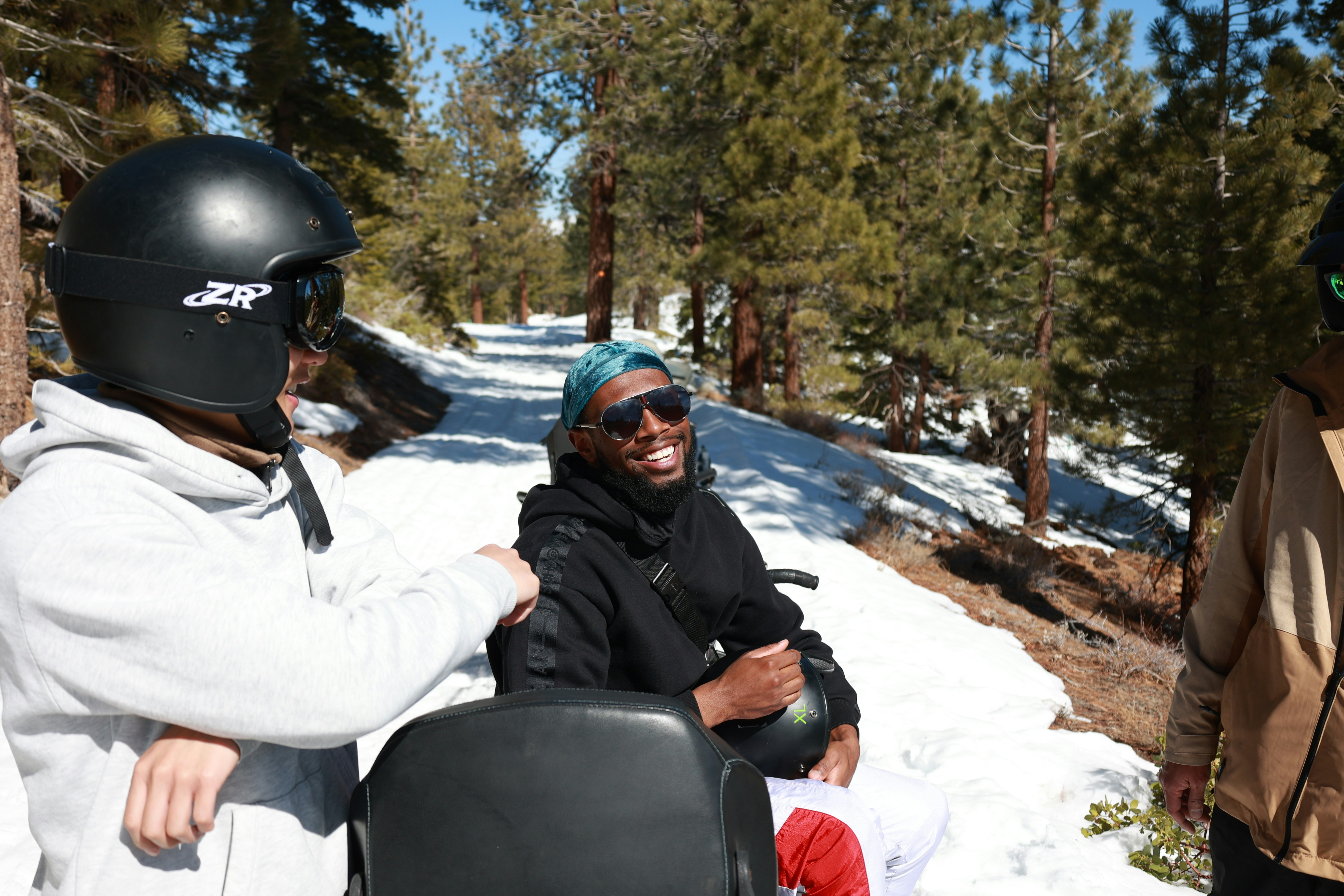 Sunlit Snowfield Laughs: Friends on a Pine-Dotted Slope