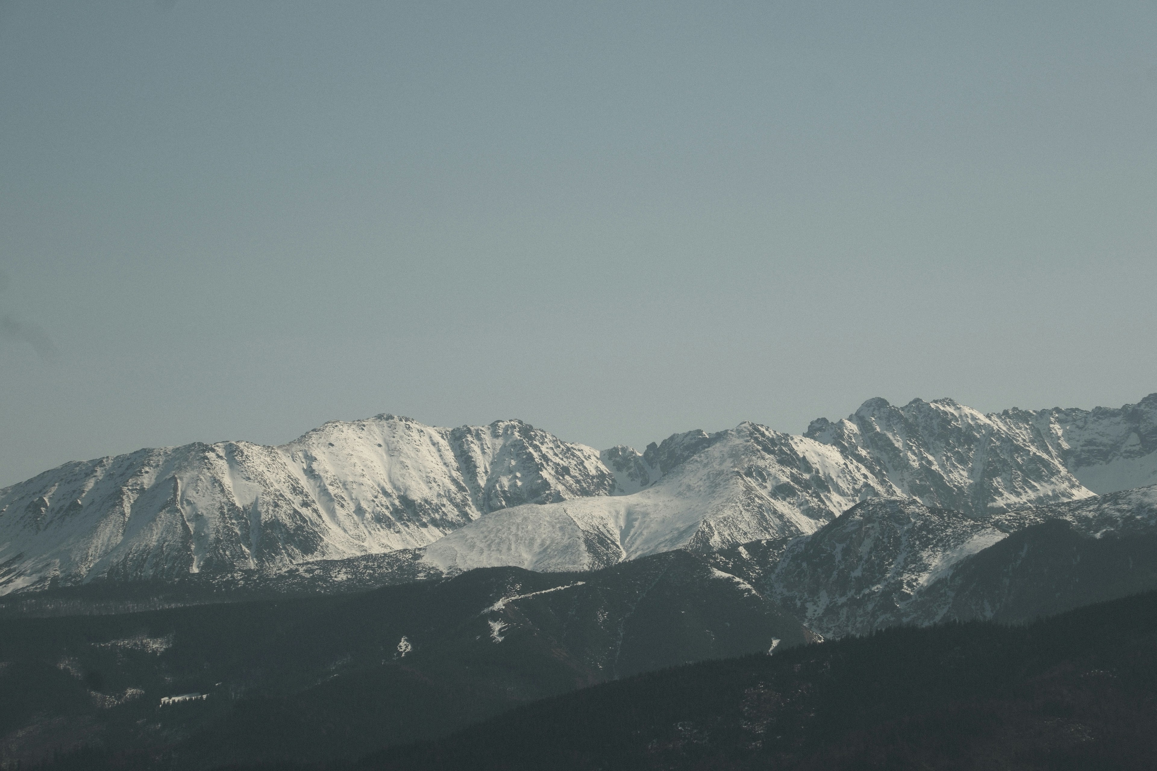 Majestic mountain range adorned with a blanket of snow under a clear sky.
