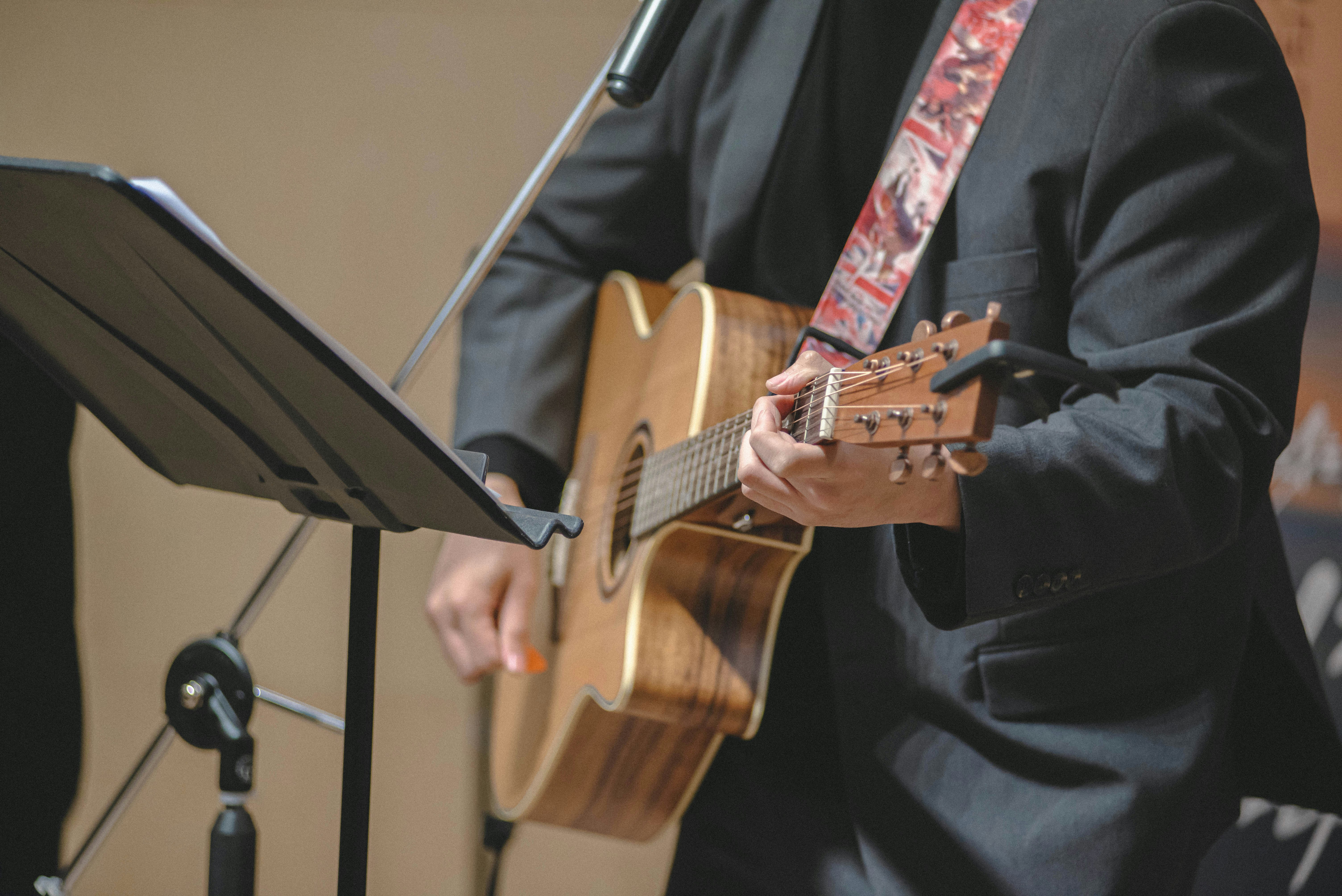 A man plays guitar with a music stand.