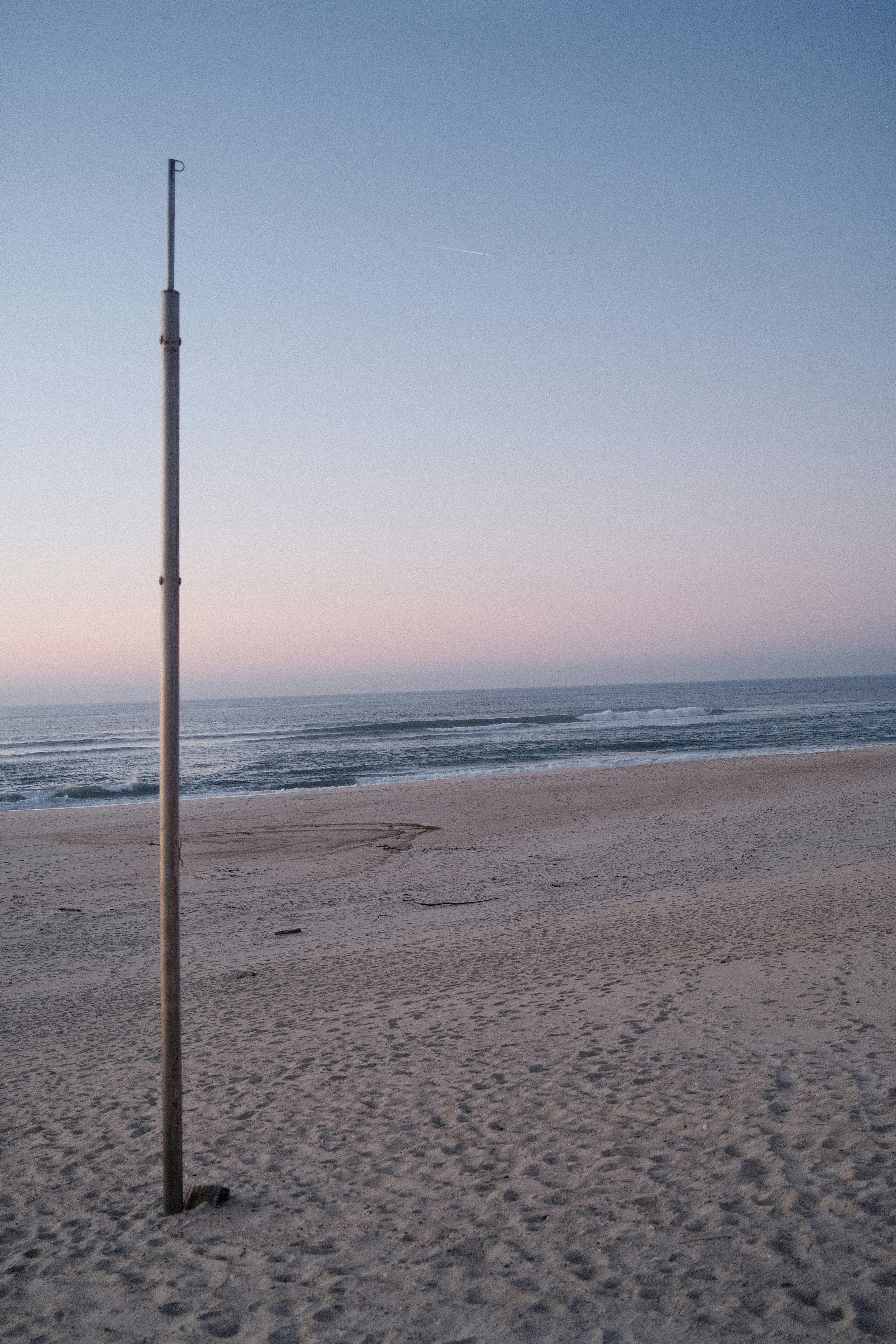 A beach with a pole facing the ocean. photo – Free Beach Image on Unsplash