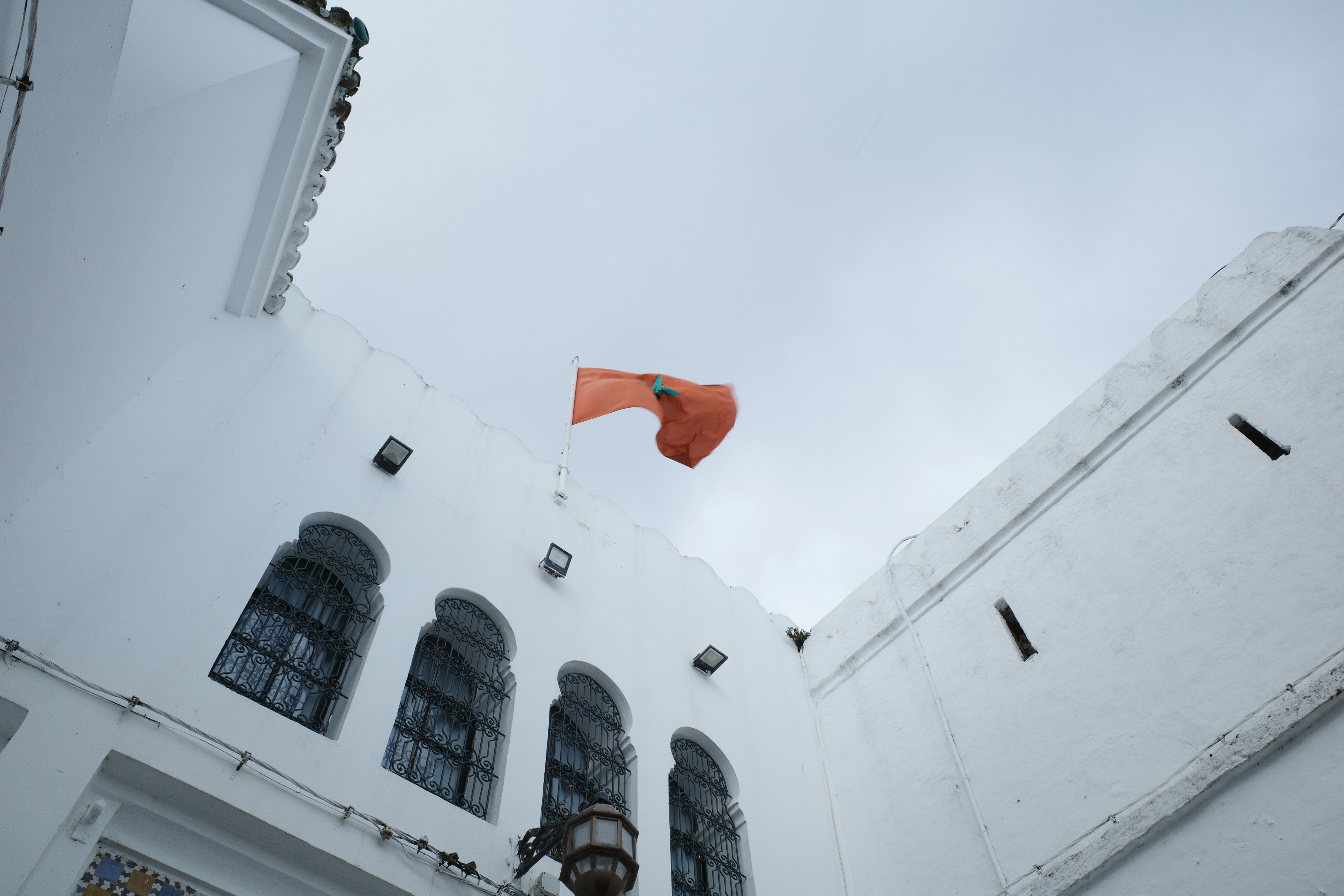 The moroccan flag waves above a white building. photo – Free Building ...