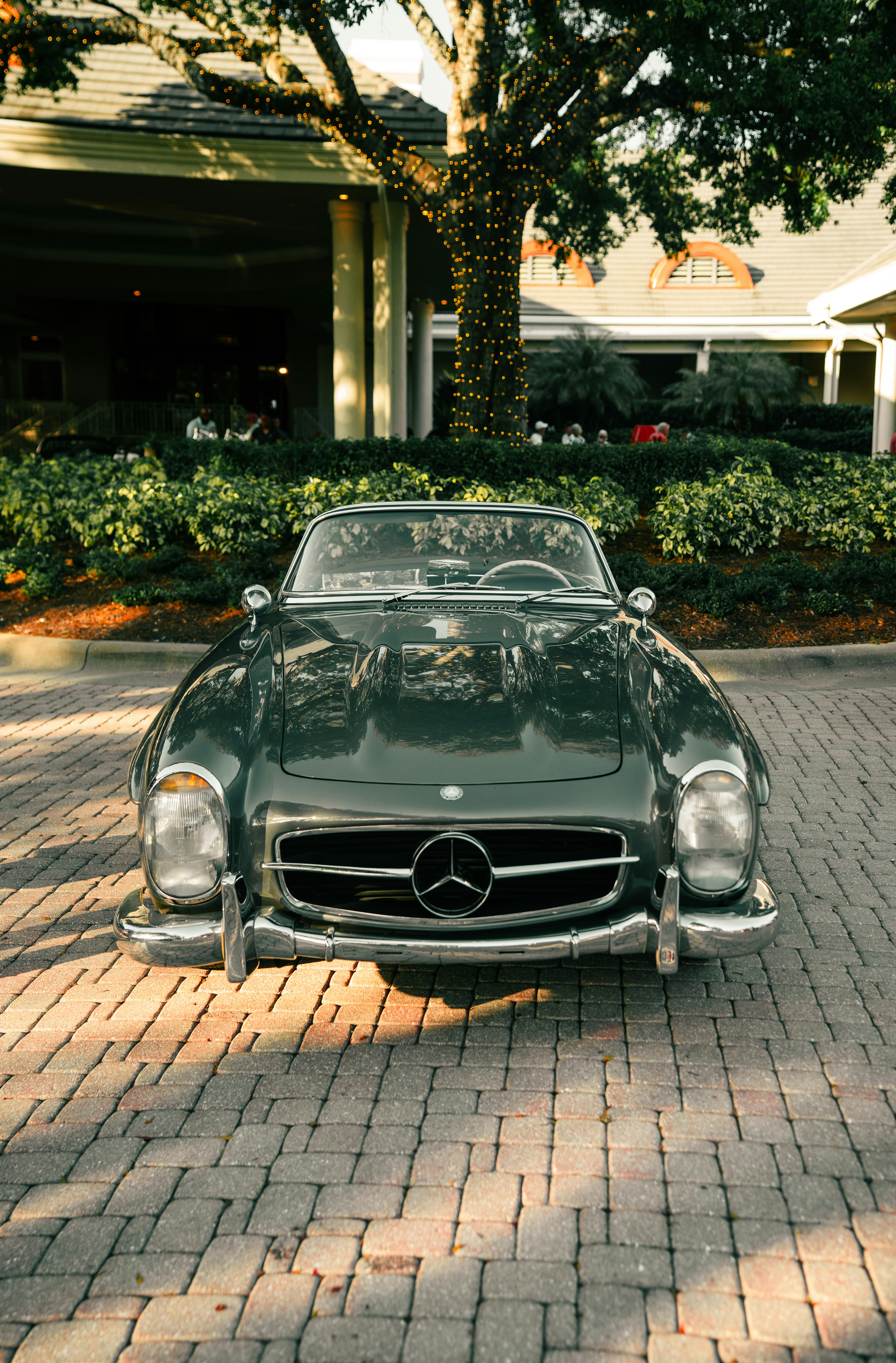 A vintage mercedes-benz is parked in front of a hotel.