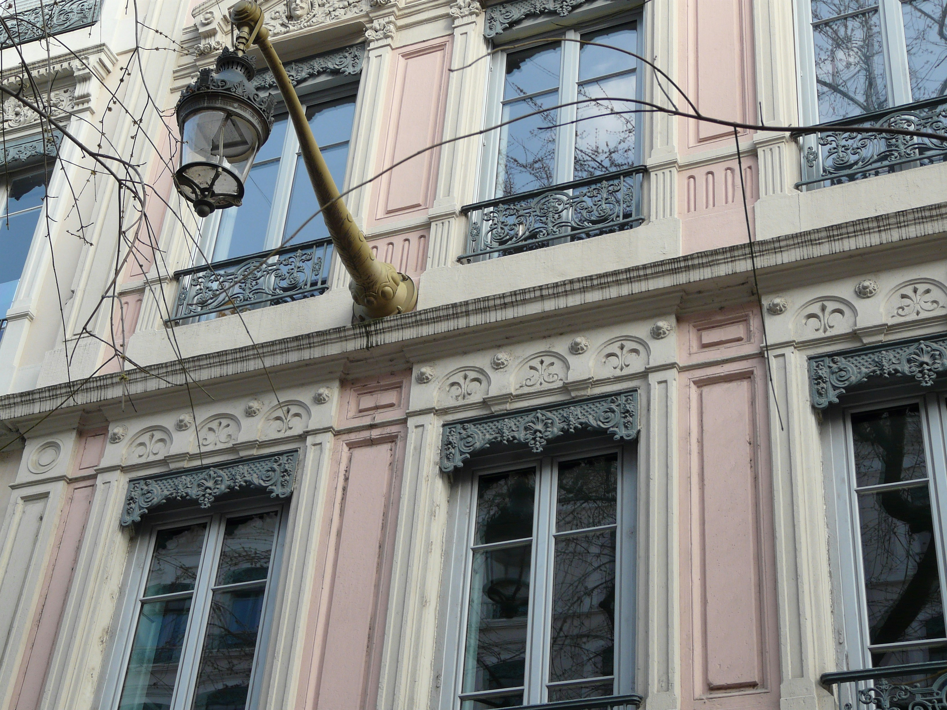 Ornate building facade with intricate moldings and a vintage street lamp extending outward.