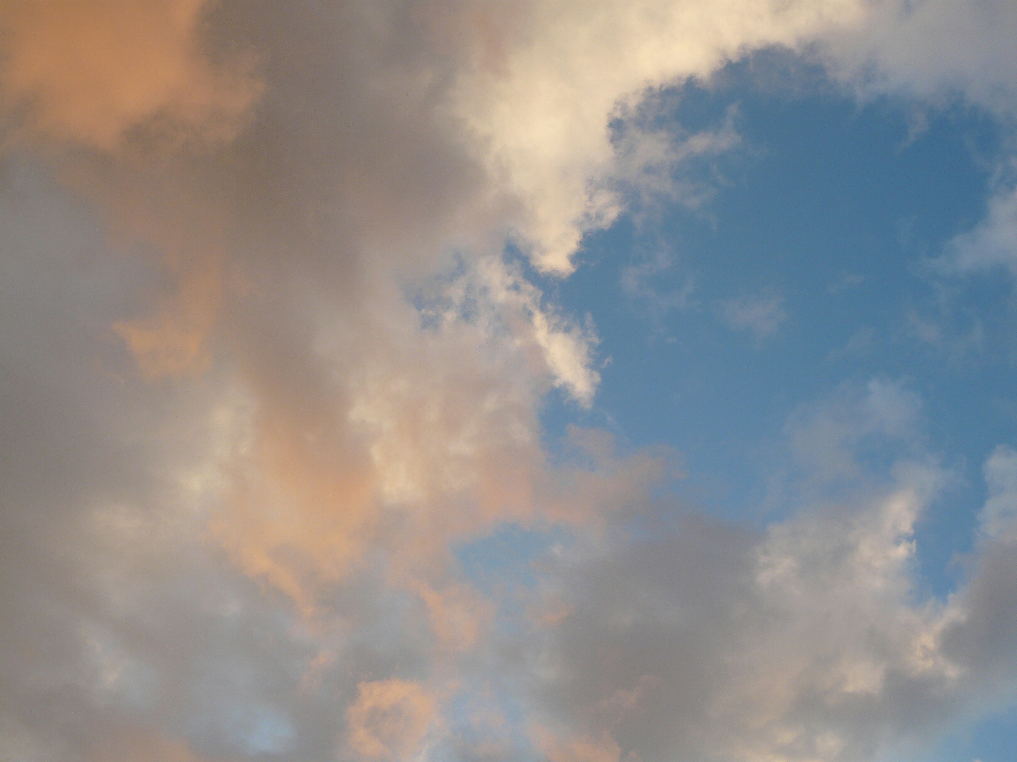 Soft clouds tinged with warm sunset colors against a clear blue sky.