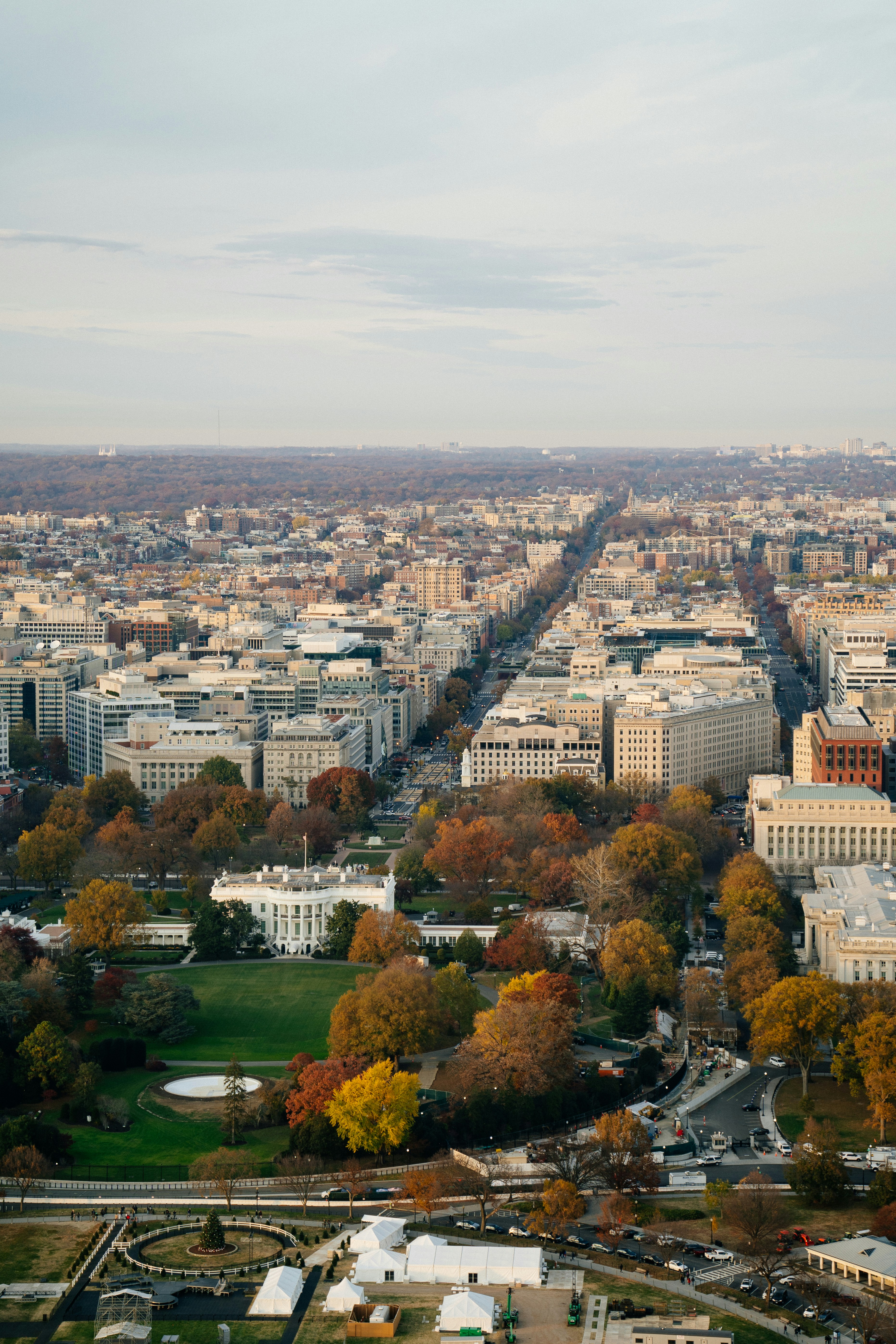 Aerial view of the White House surrounded by autumn foliage with Pennsylvania Avenue stretching into the distance.