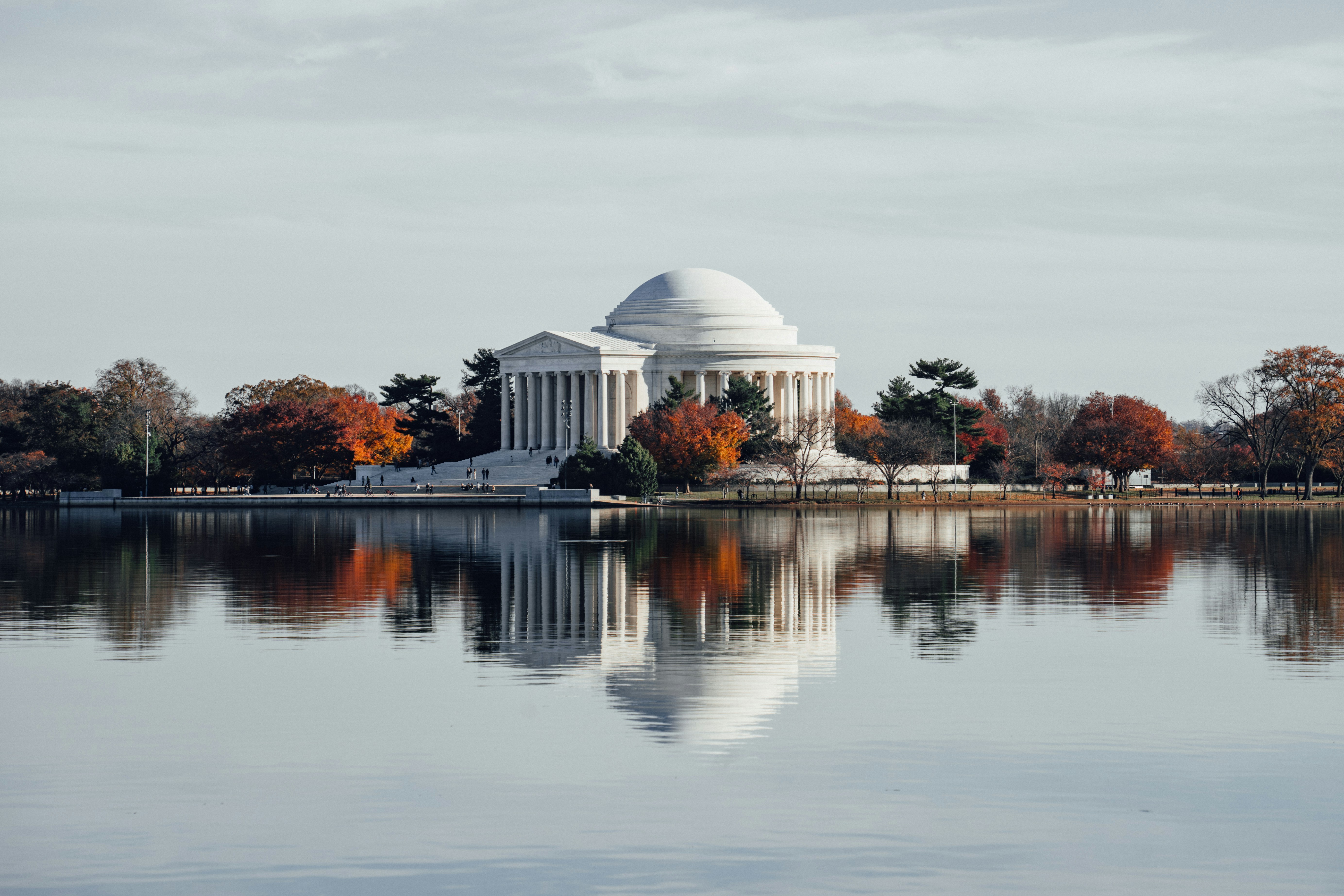 Jefferson Memorial mirrored in calm waters, surrounded by autumn foliage.