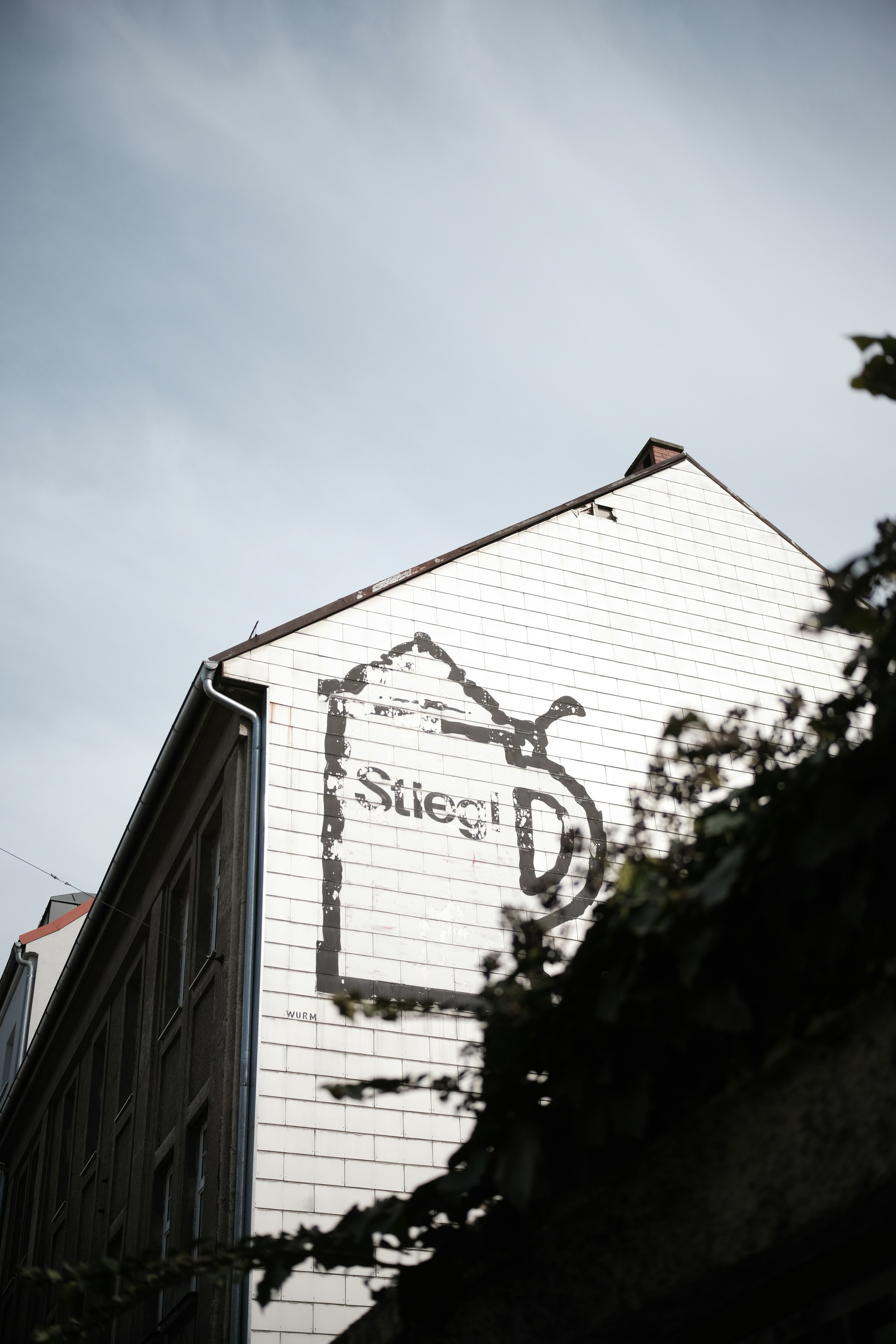 A brick wall in an urban alley is adorned with graffiti that creatively expresses local culture. The scene captures the interplay between urban architecture and street art, inviting curiosity.