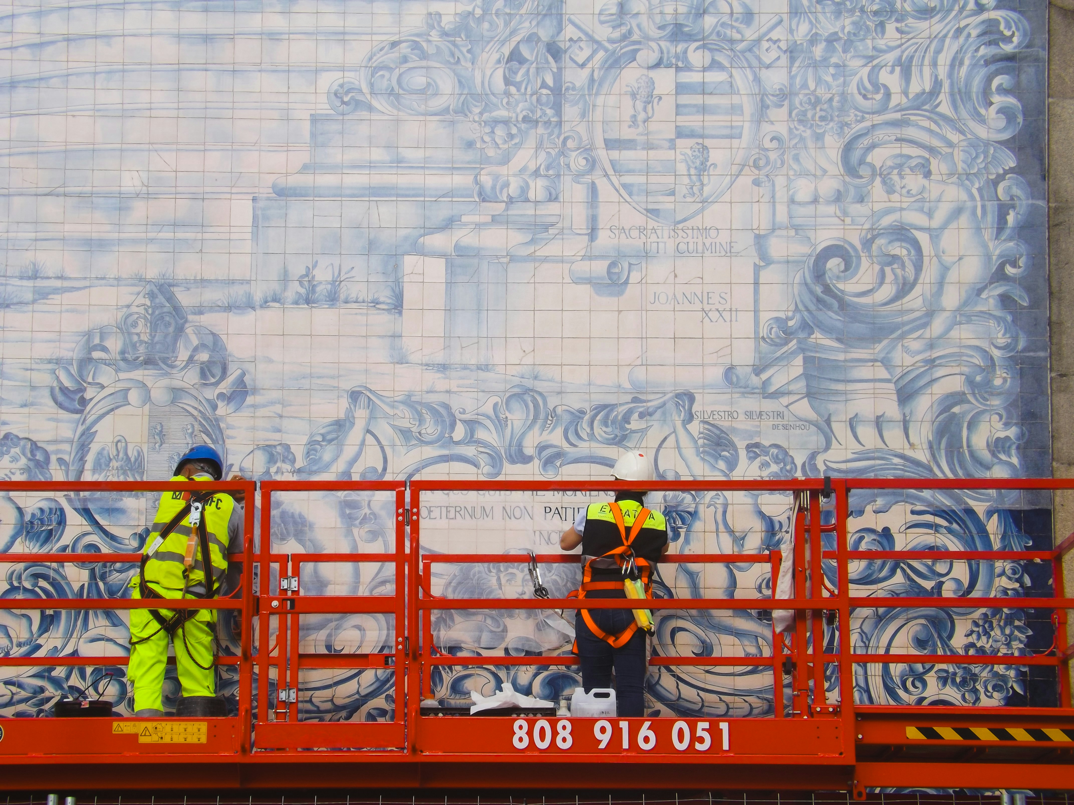 Workers restore large blue and white tile mural. photo – Free People ...