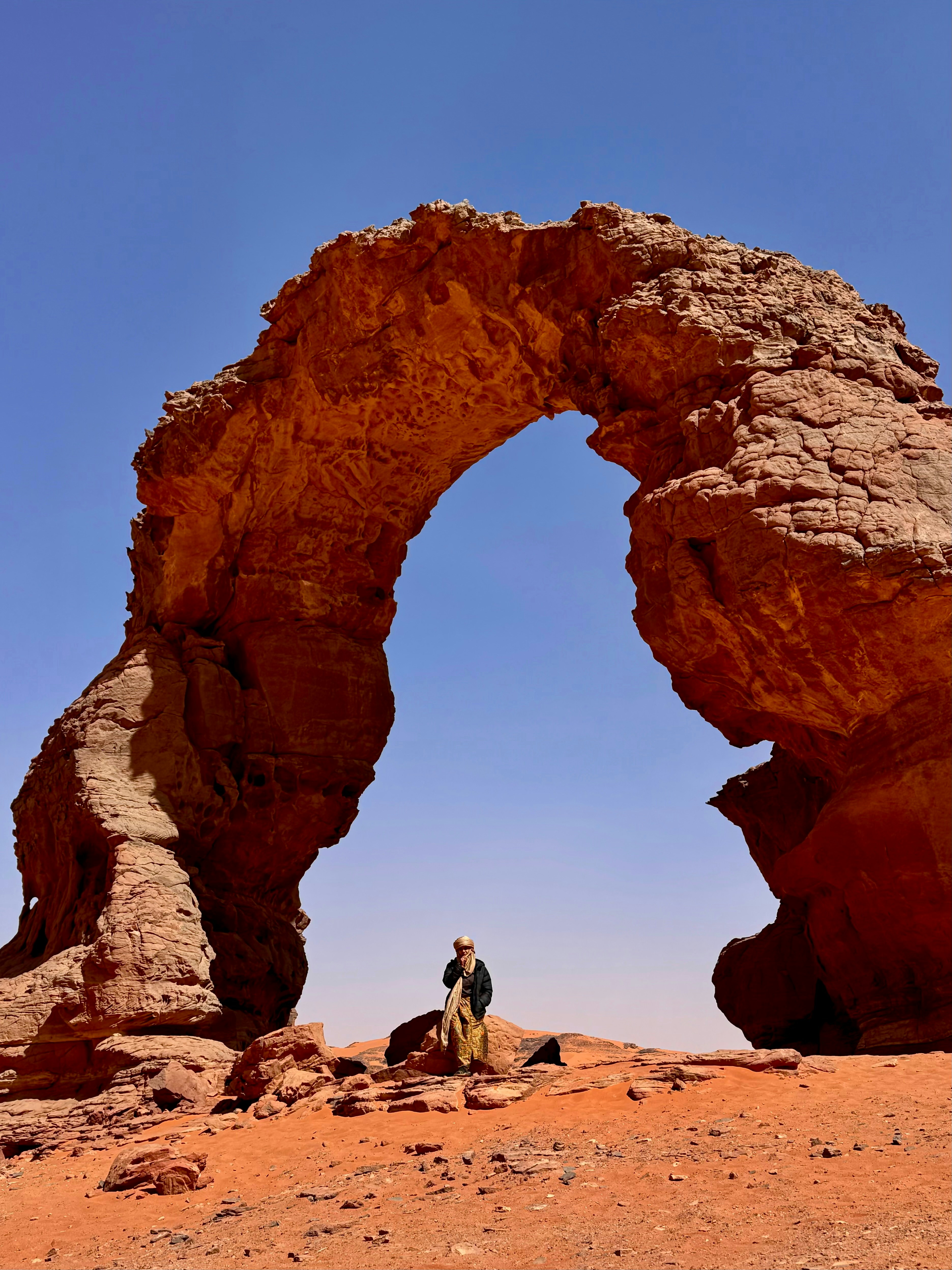 Desert Arch Monument: Lone Explorer Beneath a Crimson Rock Gate