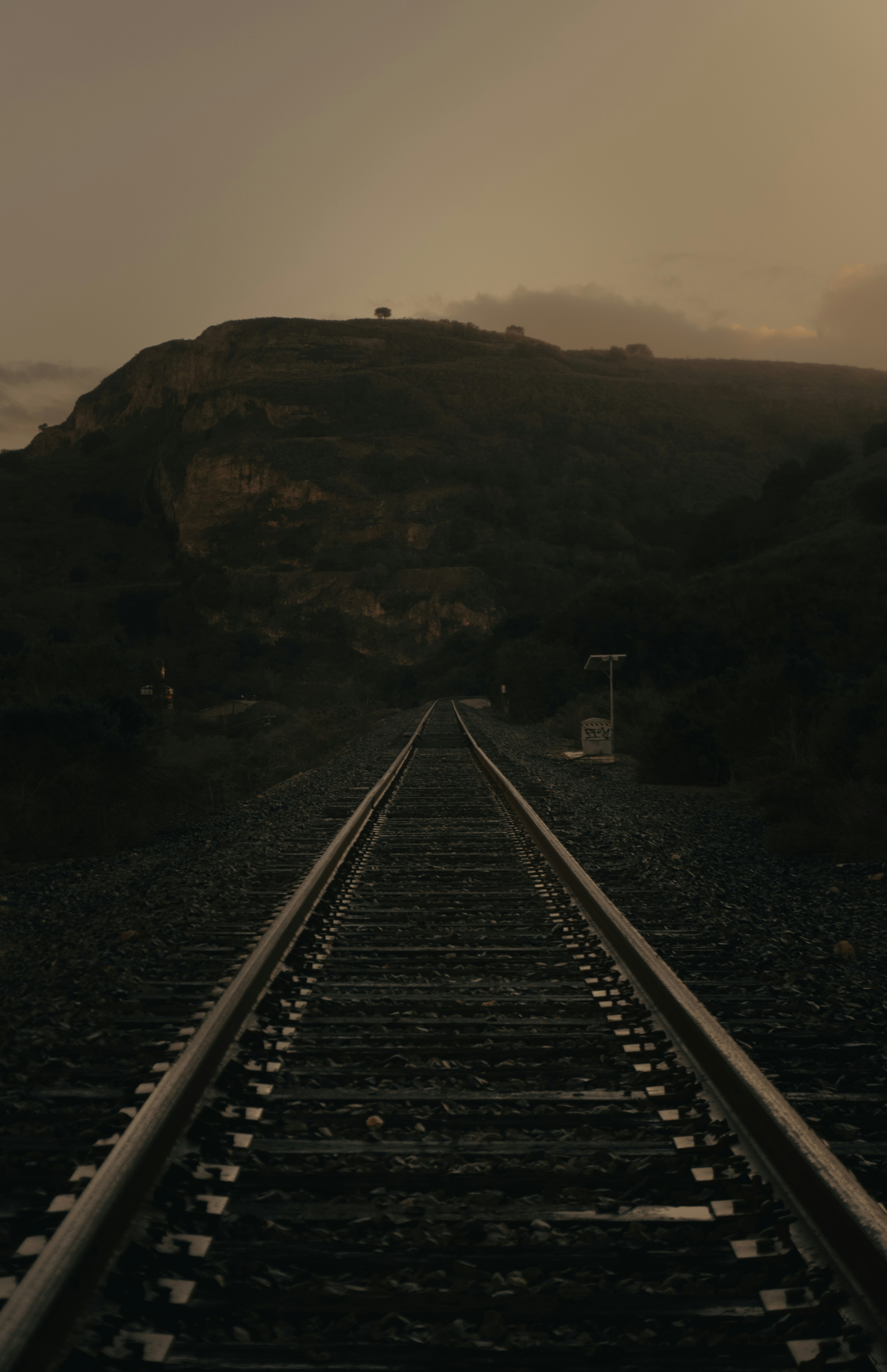 Railroad tracks lead toward a distant mountain.