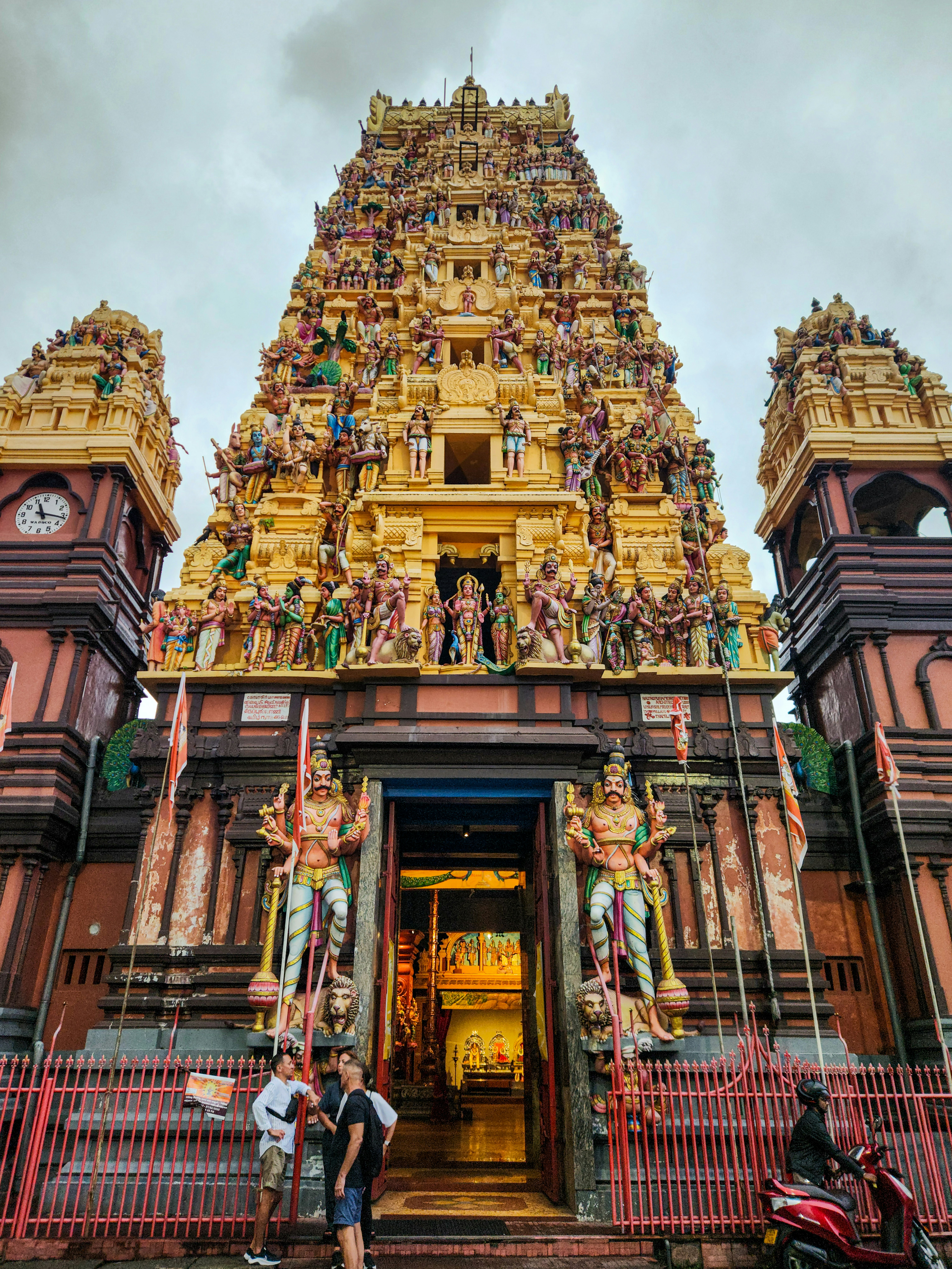 Ascending Gold: A Multistory Gopuram Adorned with Deities Against a Cloudy Sky