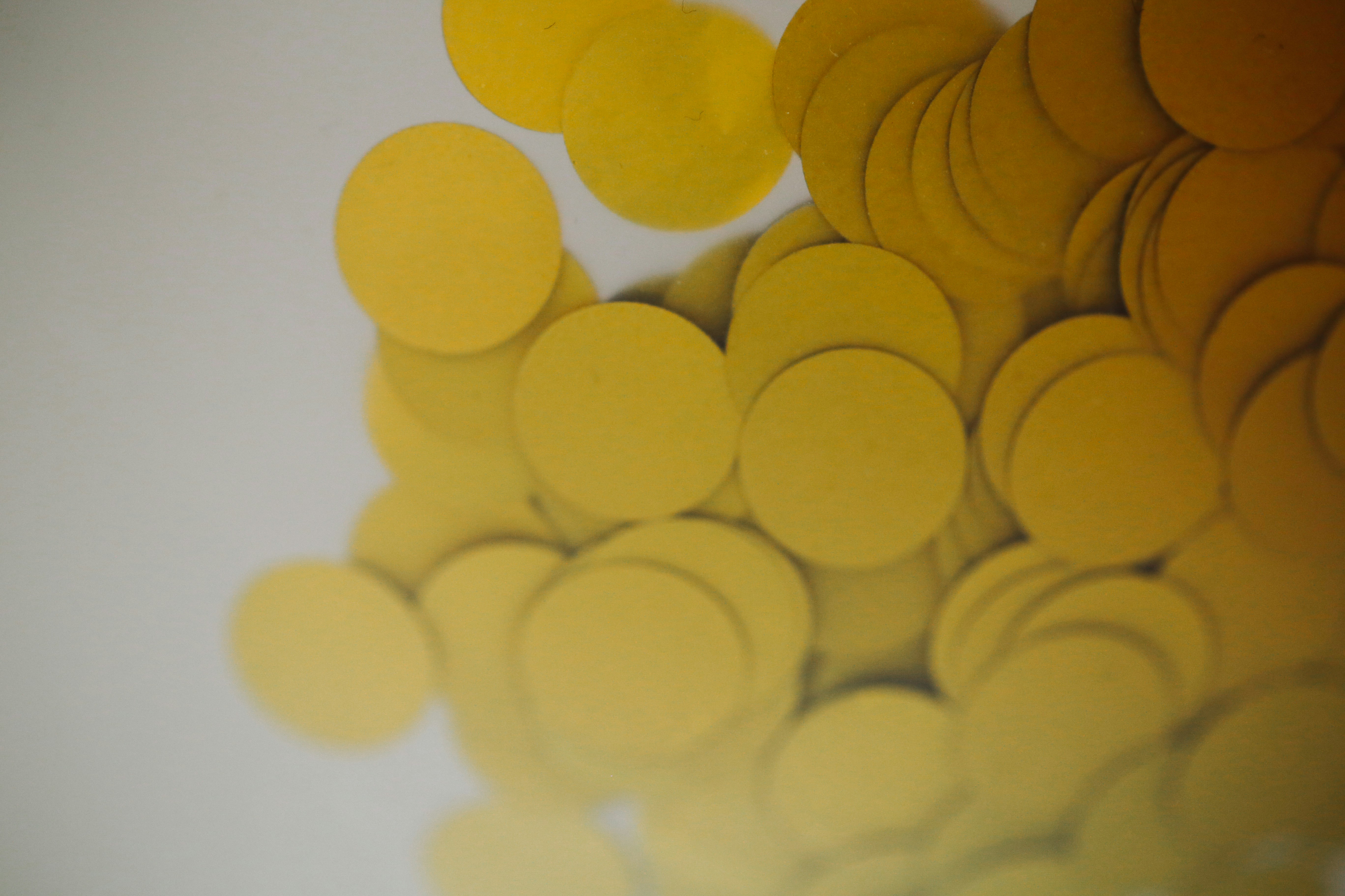 Foto Lingkaran confetti kuning tersebar di permukaan putih. – Gambar ...
