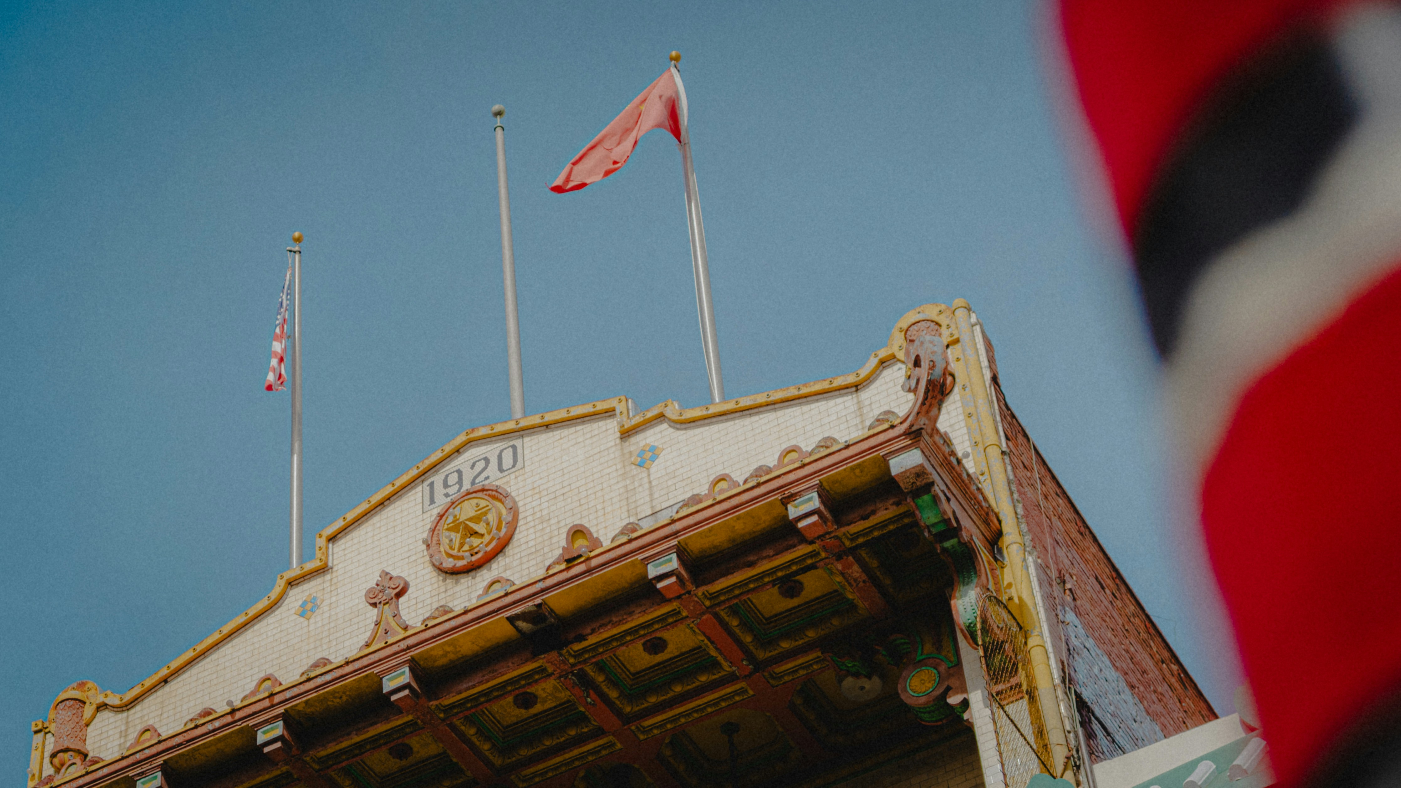 Ornate building facade with flags flying against a clear blue sky.