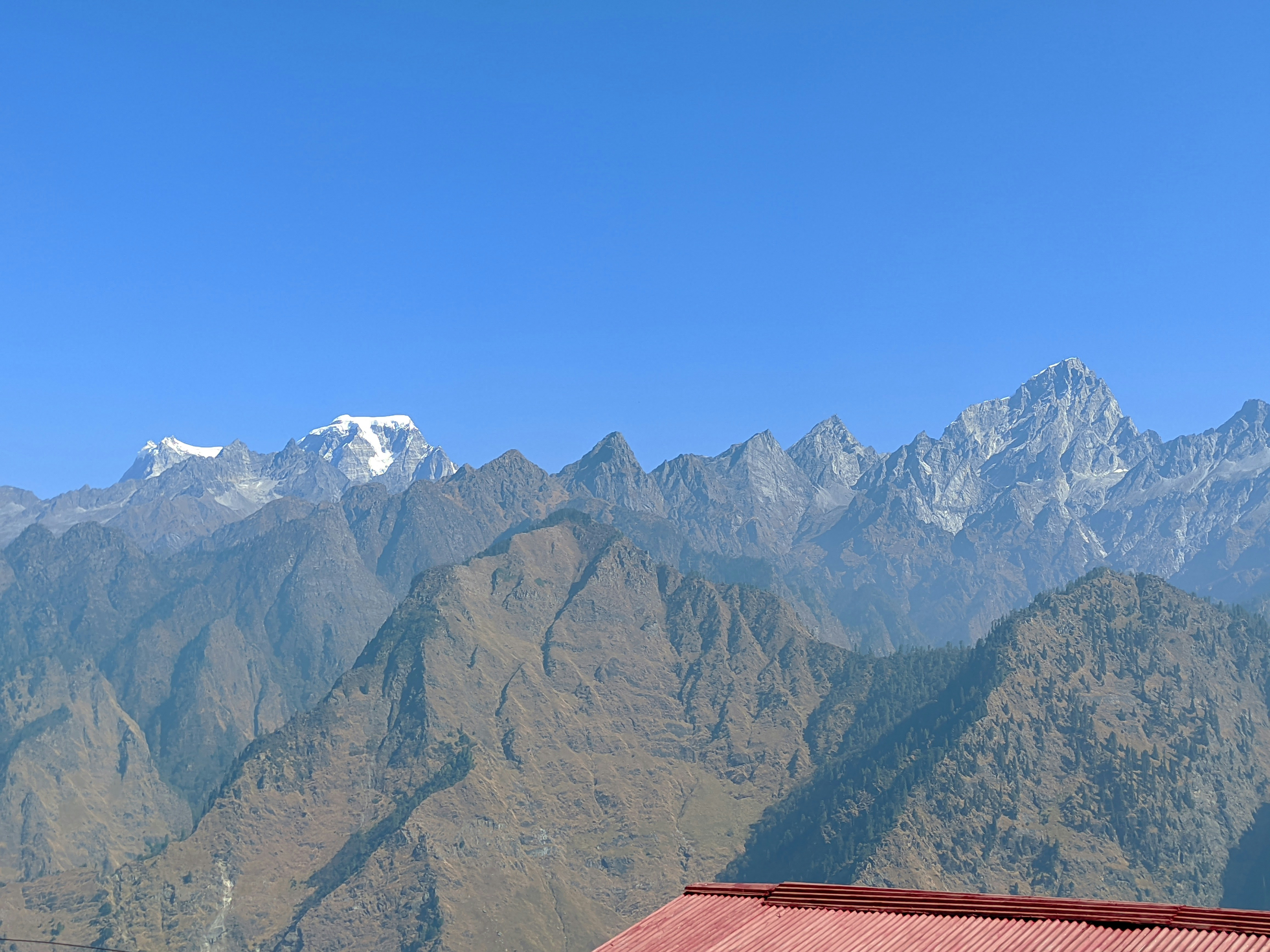 Snow-Kissed Peaks Framed by a Red Roof