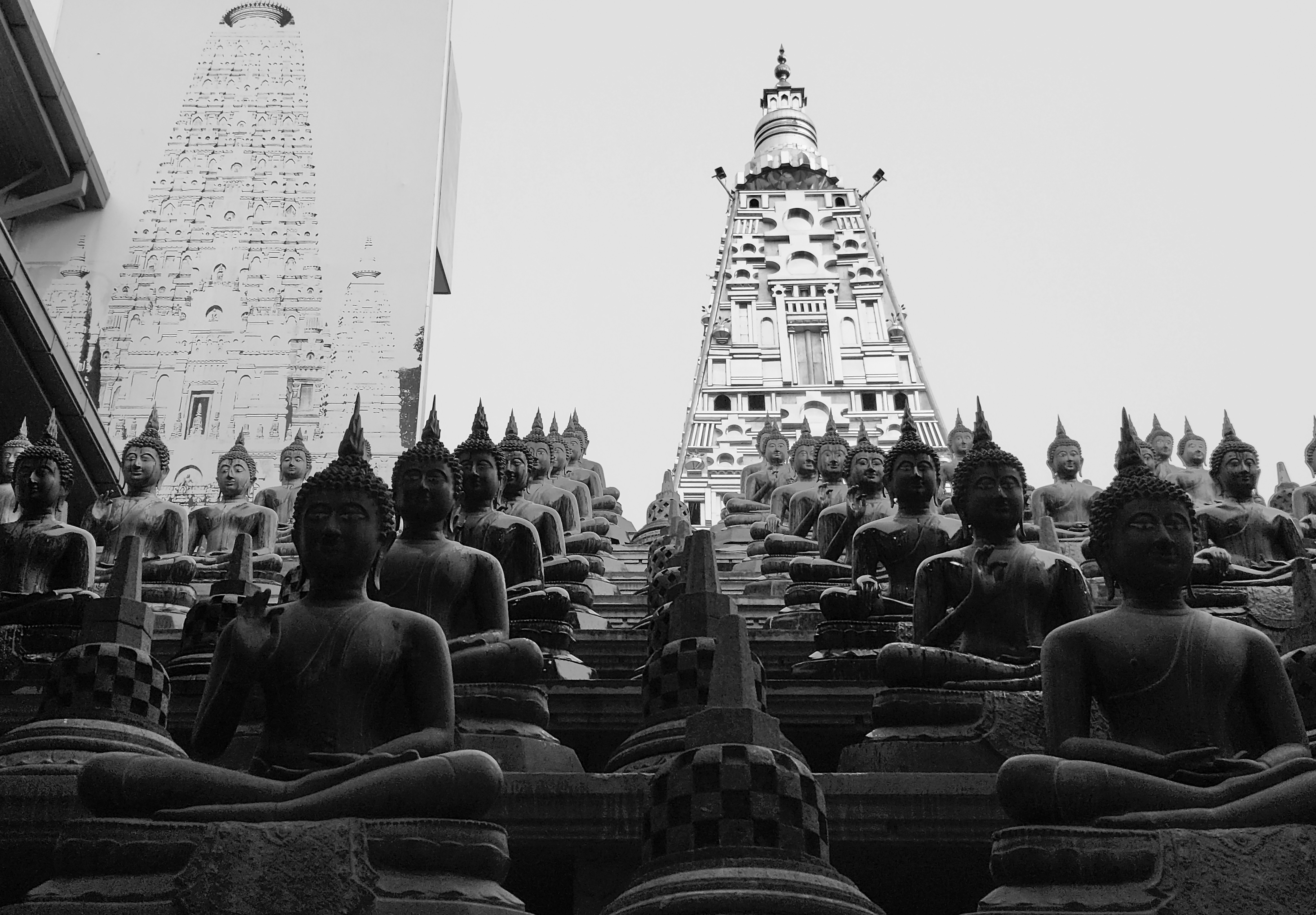 Rows of buddha statues face towering temple structures. photo – Free ...