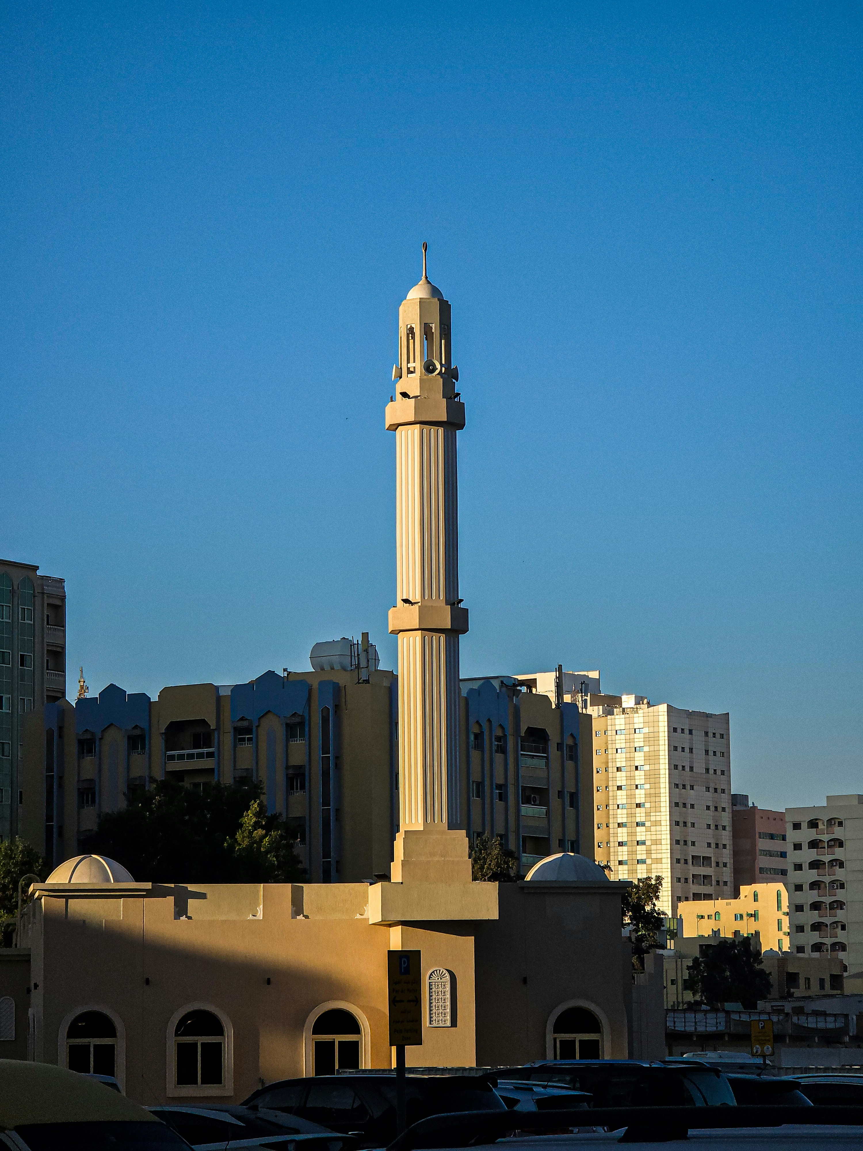 A tall mosque minaret stands in a city. photo – Free Car Image on Unsplash