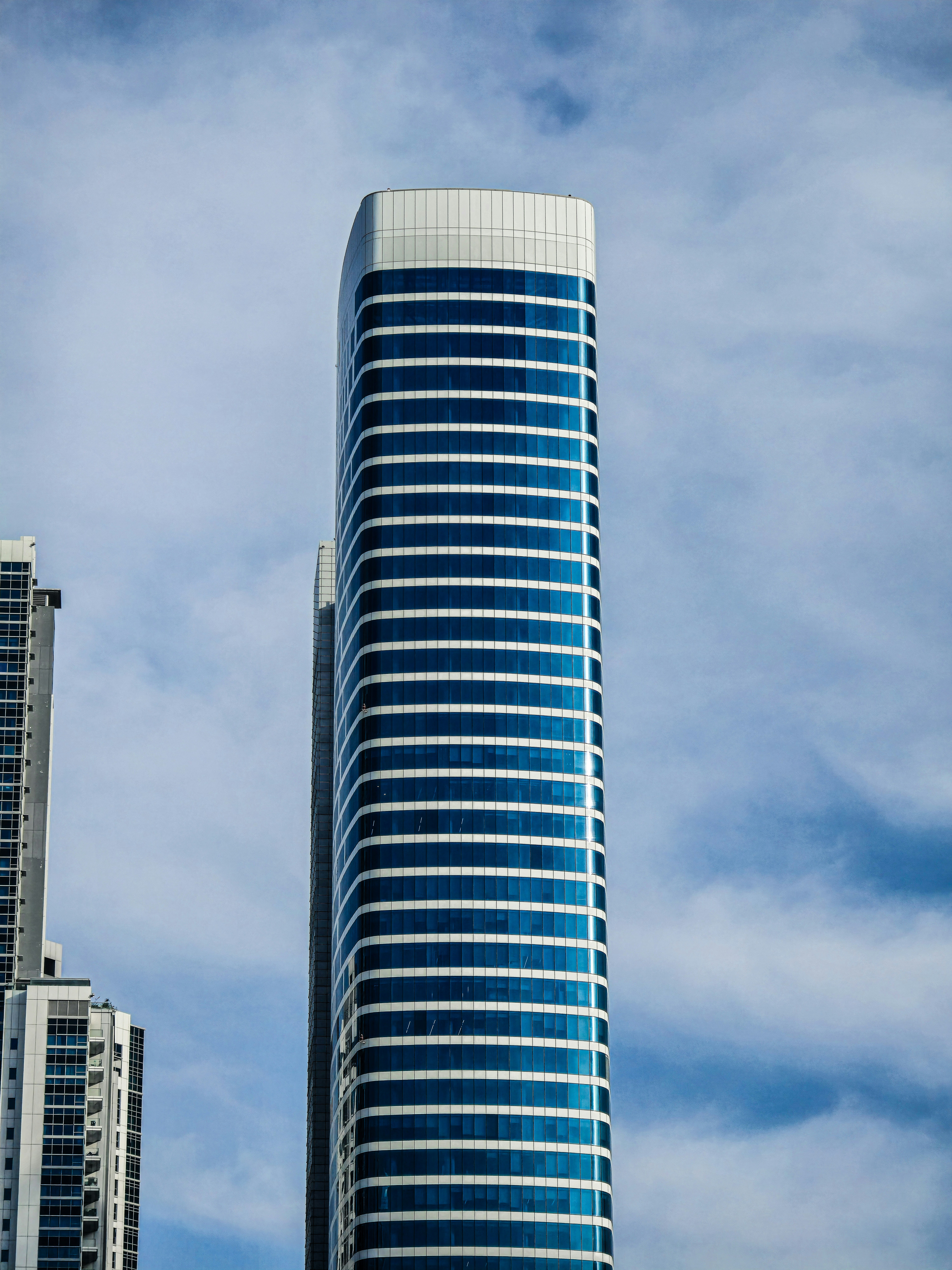 Tall skyscraper with blue windows against a cloudy sky. photo – Free ...
