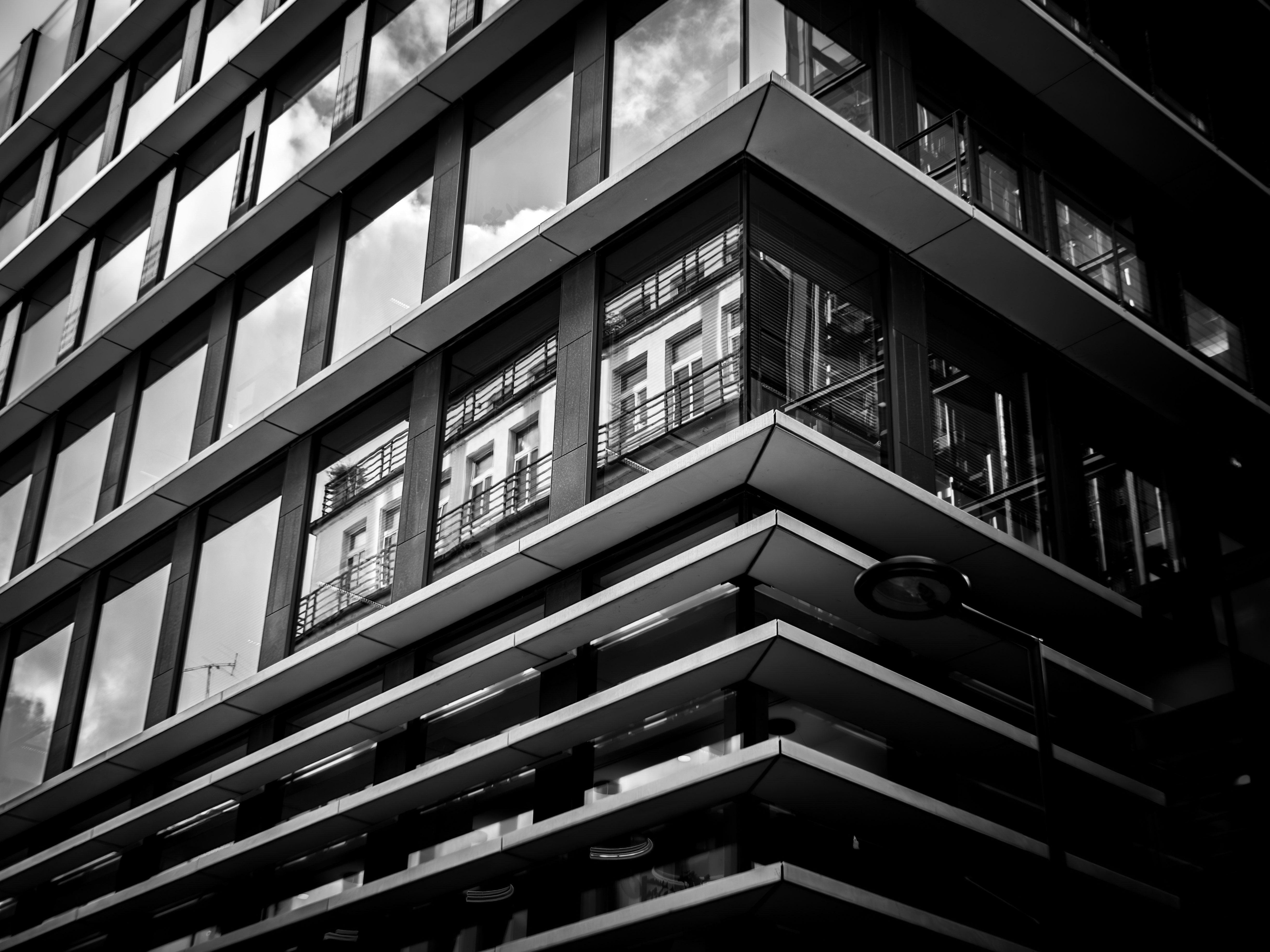 Modern building facade with reflective glass windows capturing cityscape details.
