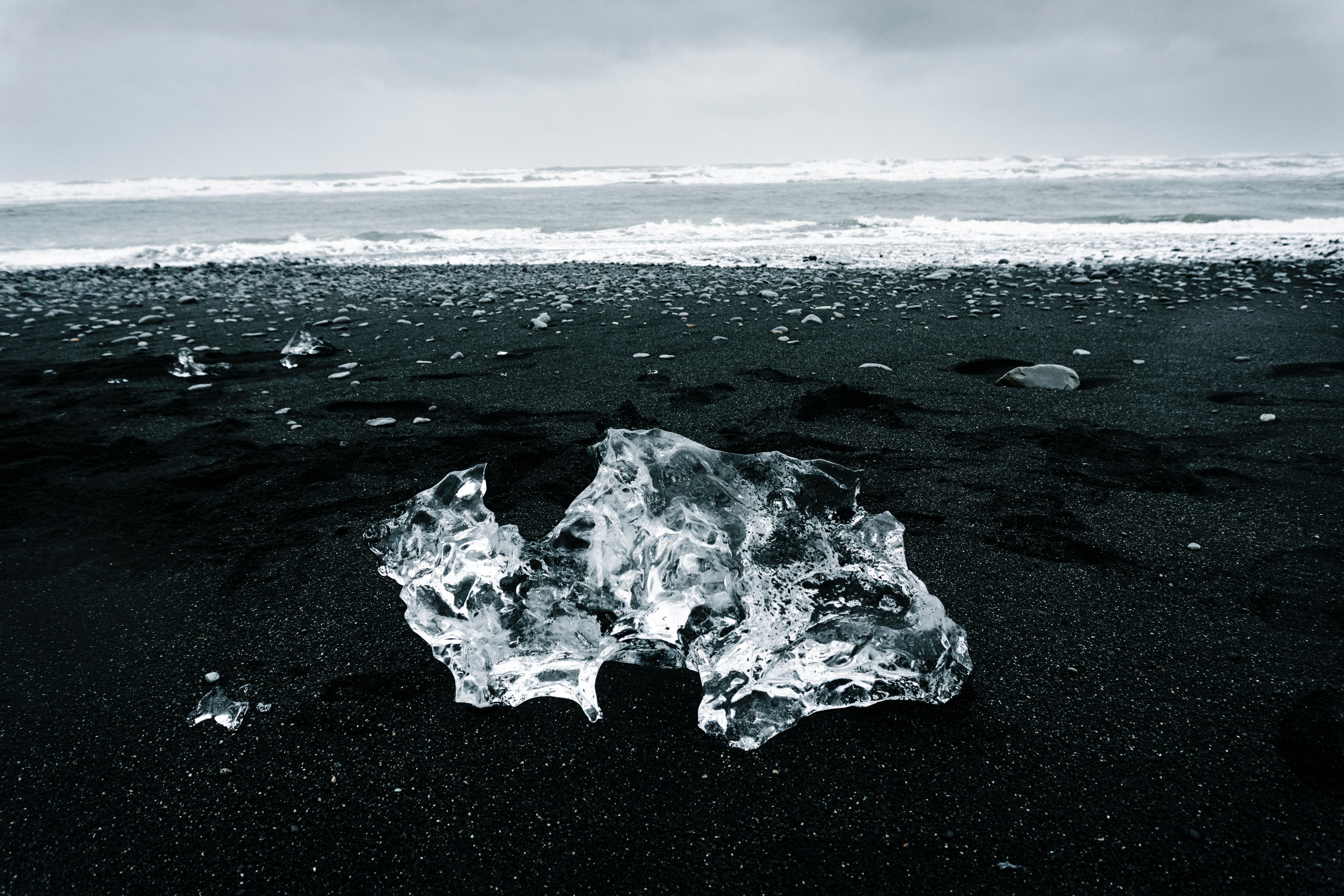 Ice washes ashore on a dark, sandy beach. photo – Free Beach Image on ...