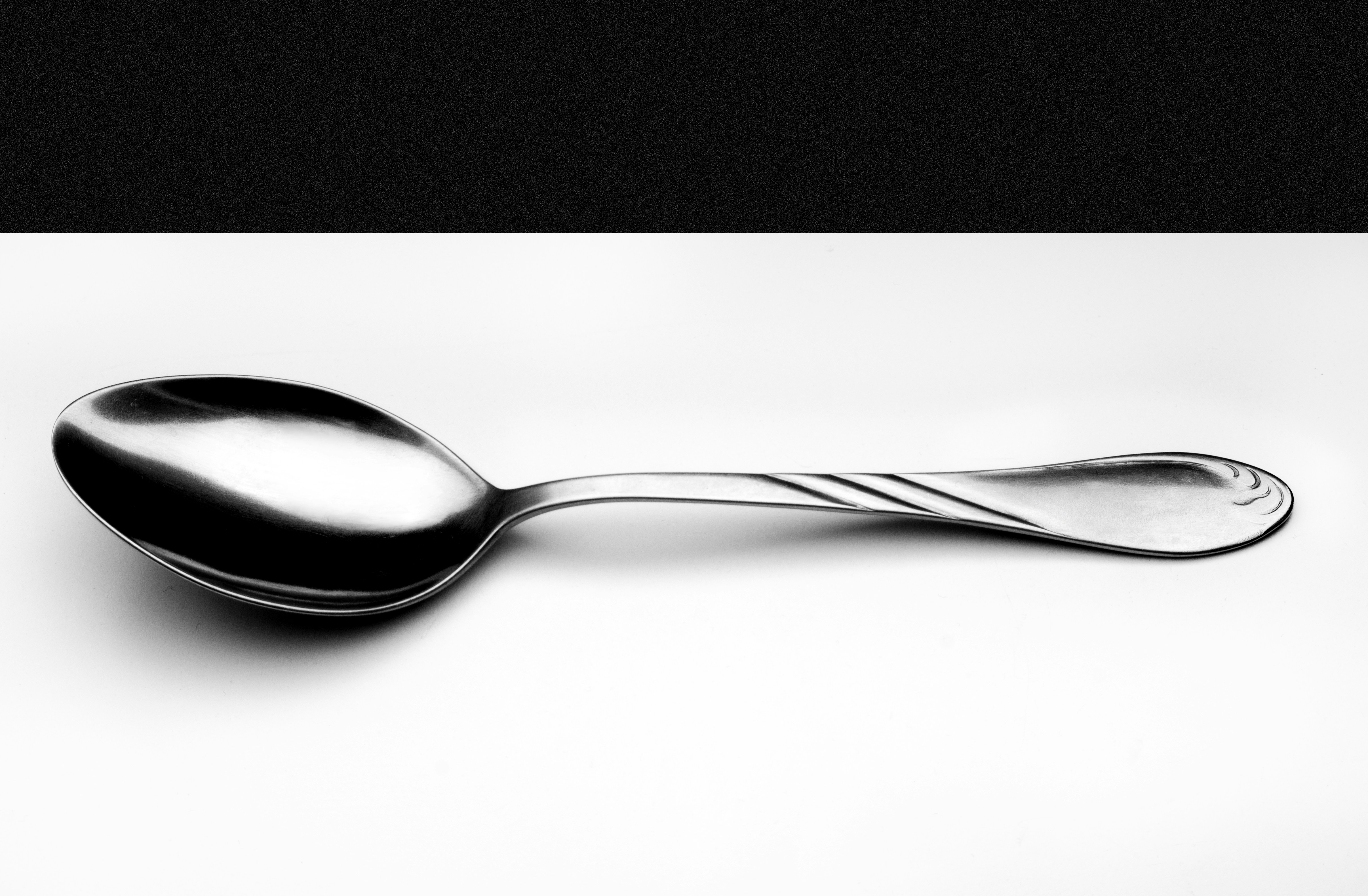 A silver spoon lies against a black and white backdrop. photo – Free ...