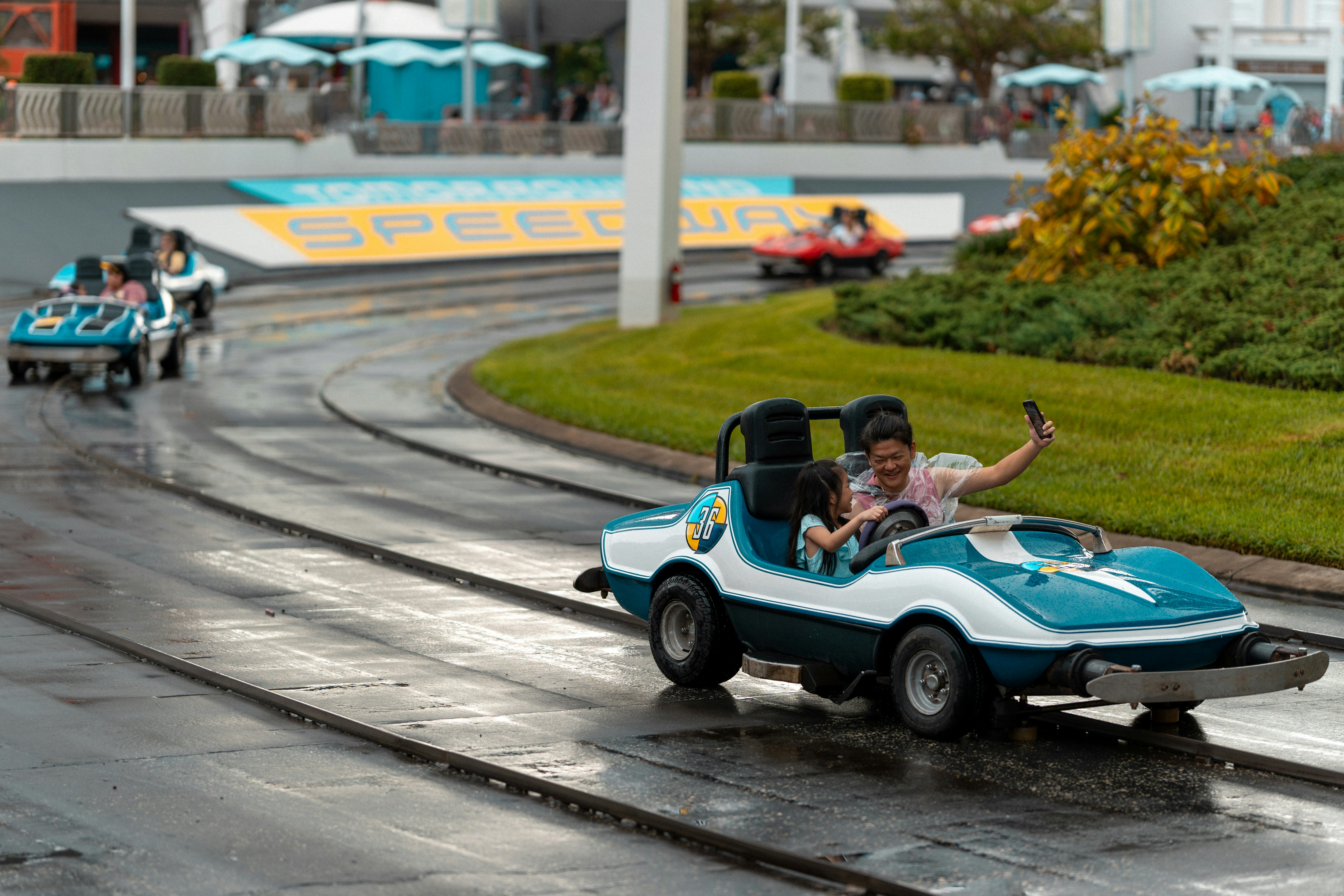 Children enjoying a ride in classic go-karts on a racetrack, with a vibrant backdrop of greenery and amusement park ambiance.