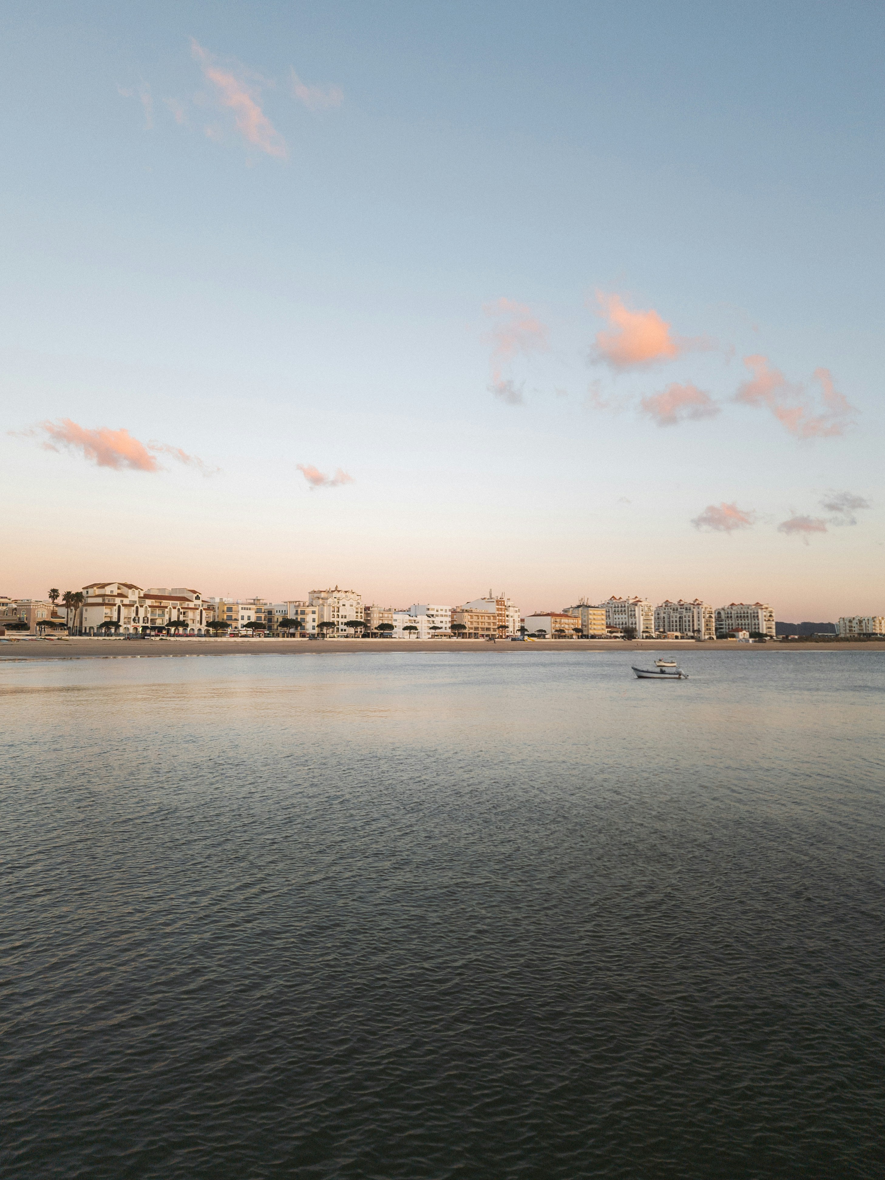 City skyline meets the sea under a calm sky. photo – Free City Image on Unsplash