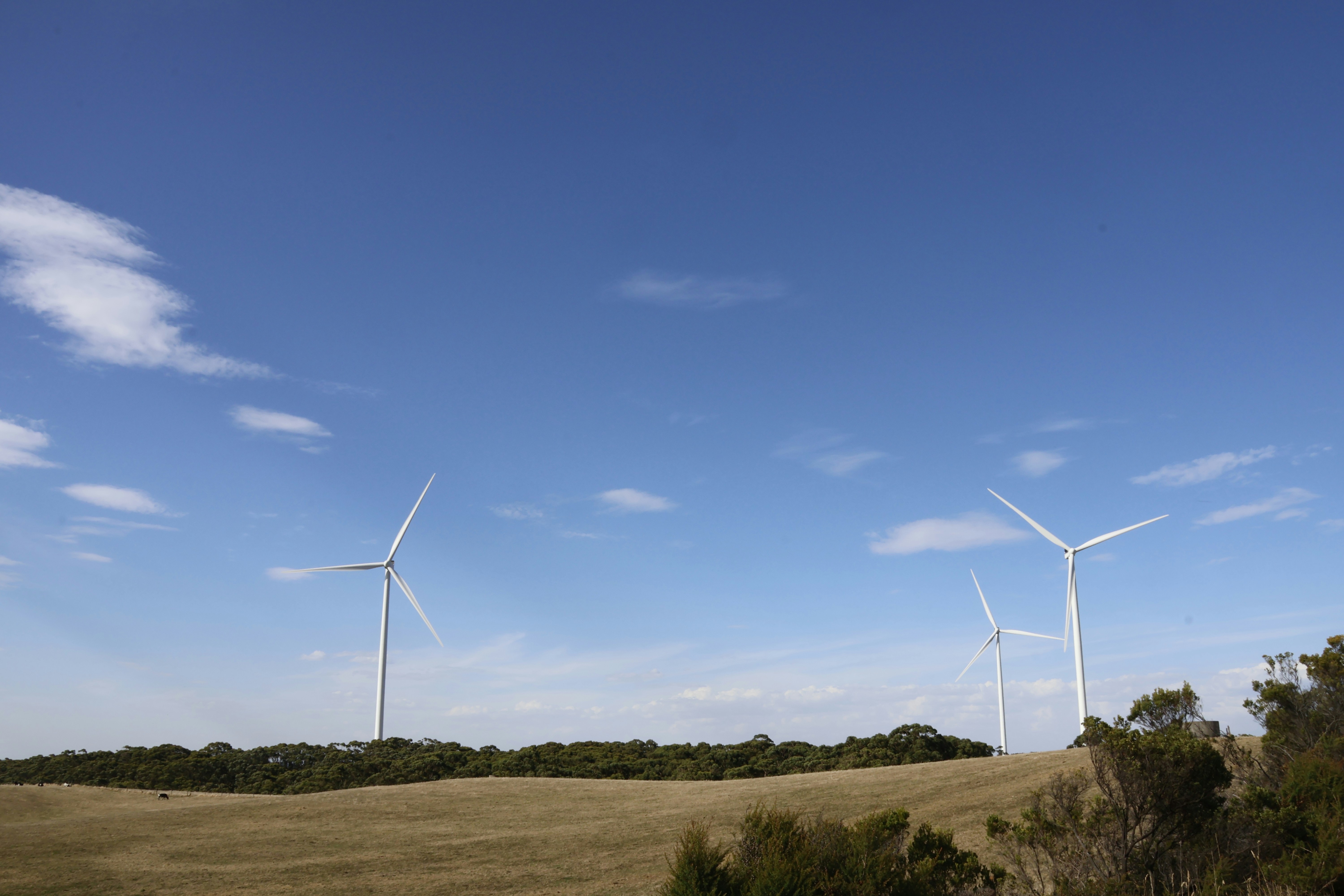 Wind turbines stand under a bright, blue sky. photo – Free Australia ...