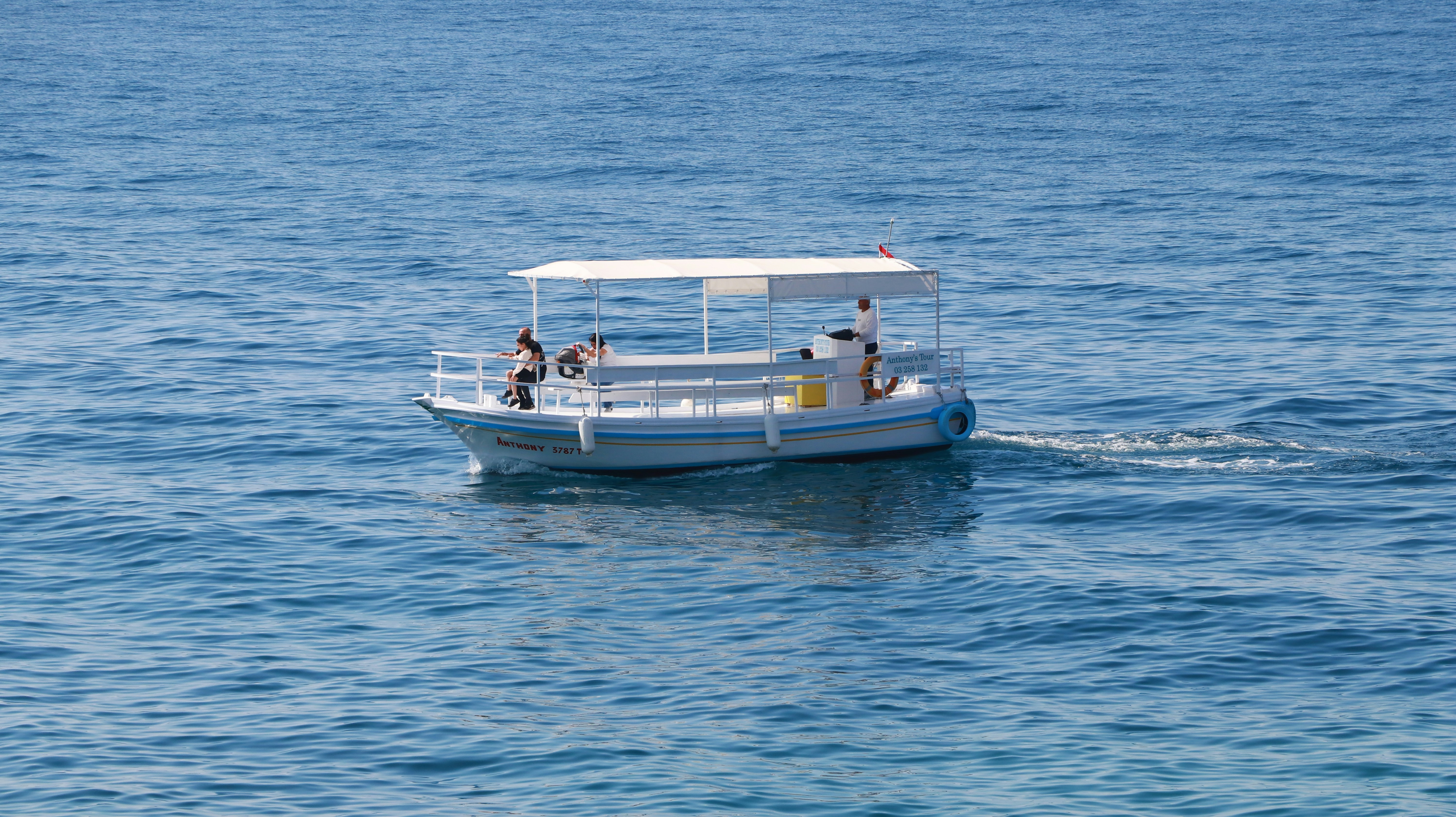 White Canopy Pontoon Gliding Across a Quiet Cerulean Sea
