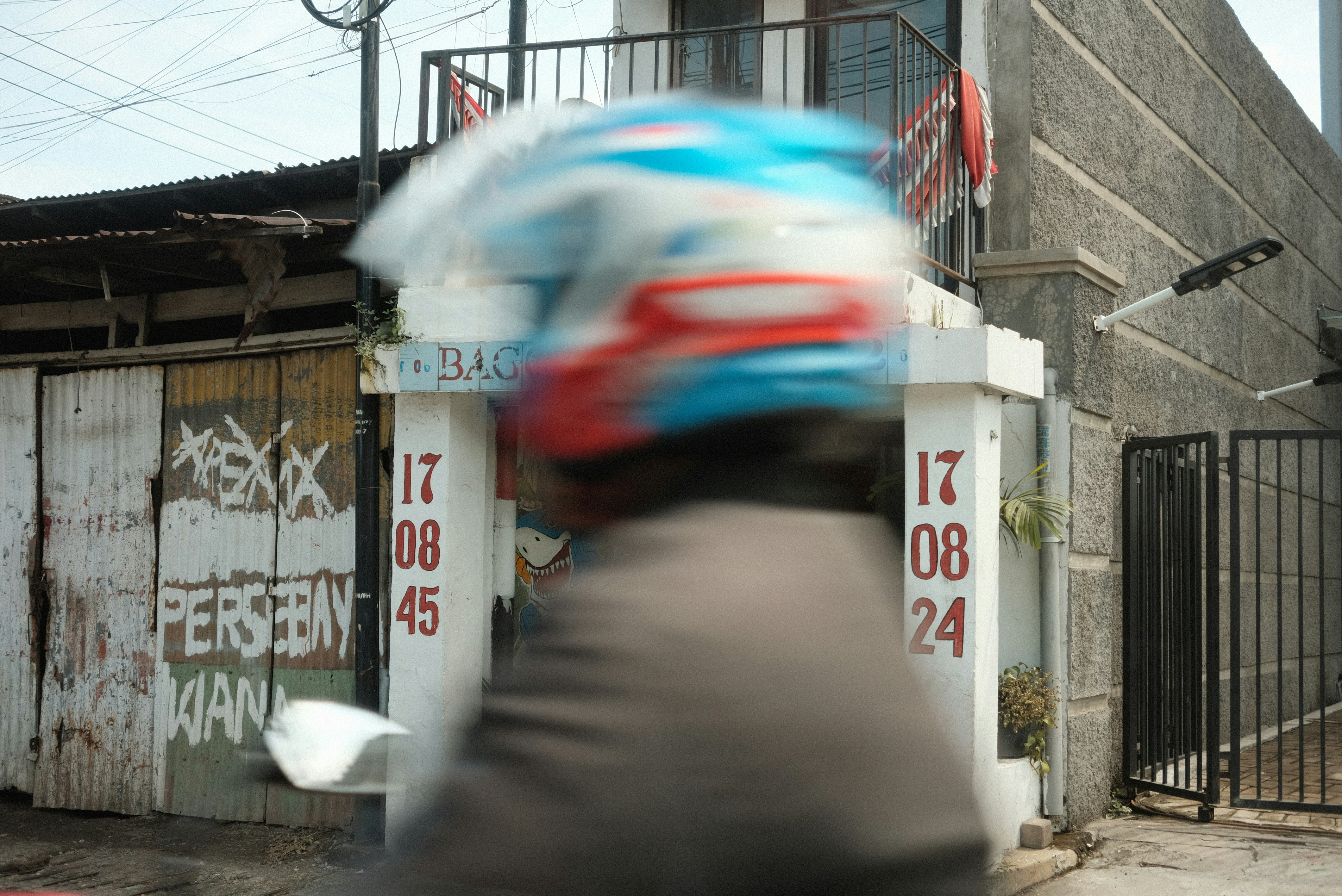 Blurred motorcyclist passing by graffiti-covered building in an urban setting.