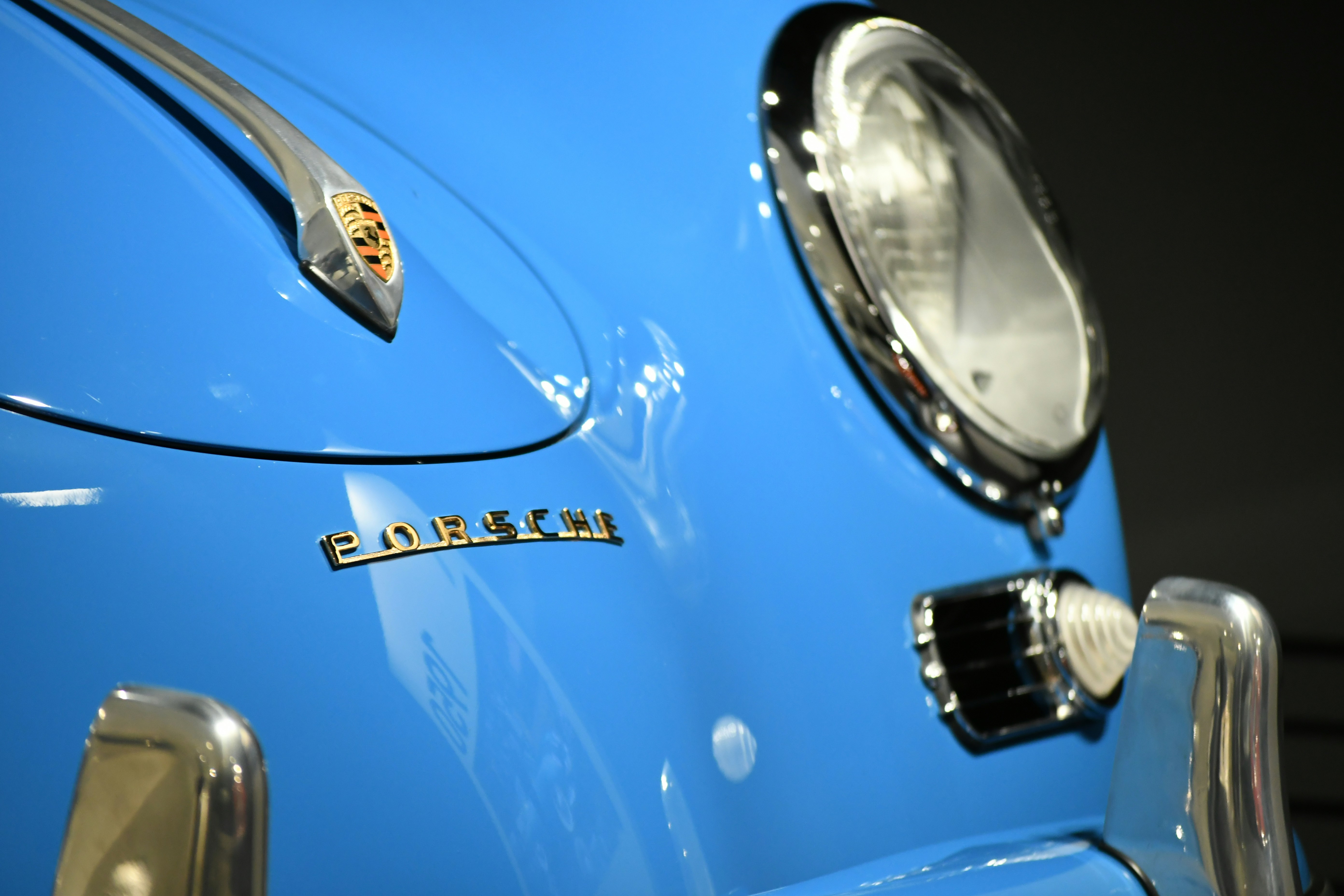 Azure Porsche Hood: Chrome Crest and Curved Silhouette in Studio Light