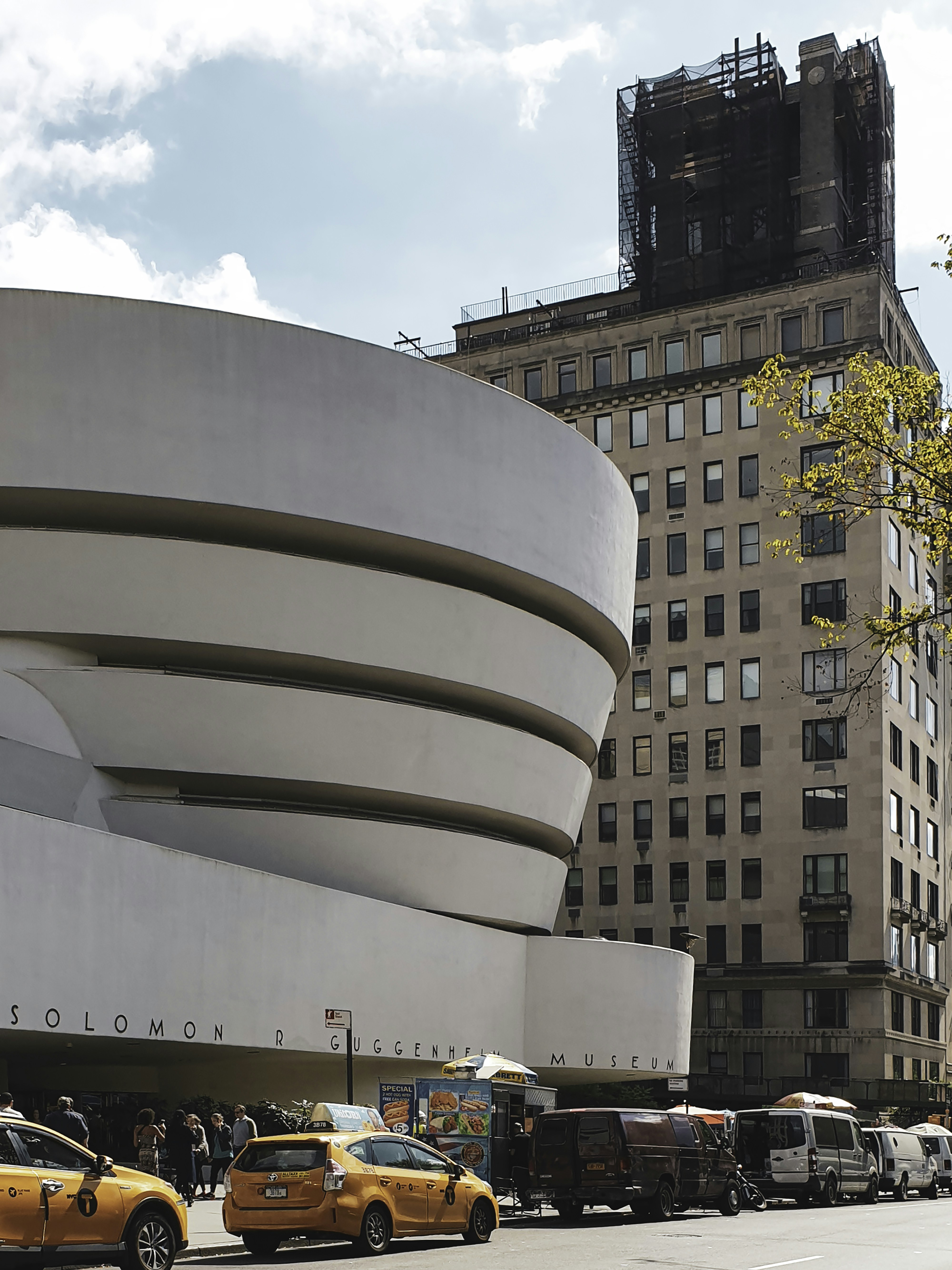 Architectural contrast between the Guggenheim Museum's spirals and a classic rectangular building on a sunny day.