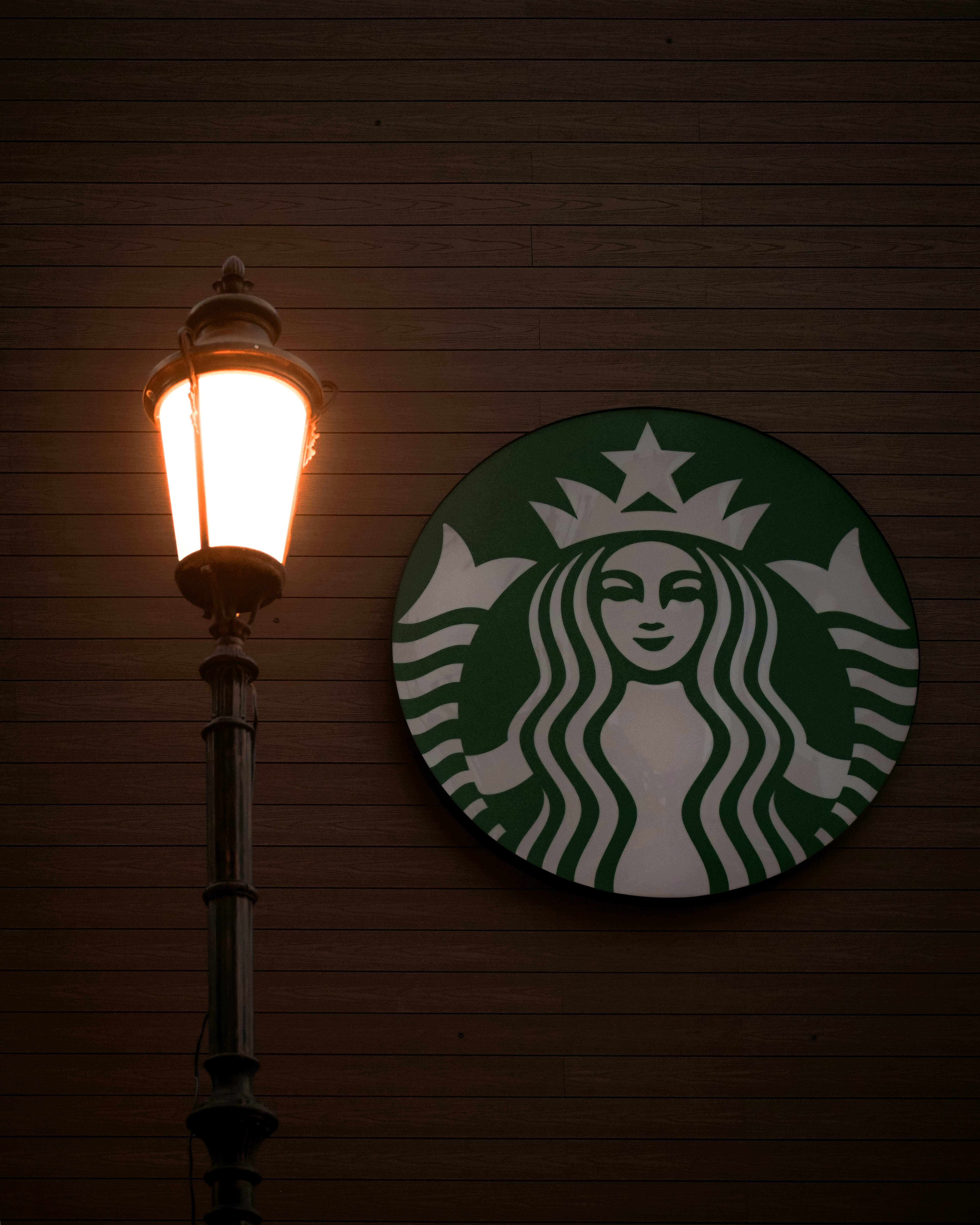 Amber Glow Meets Green Emblem: Starbucks Sign Under Streetlight