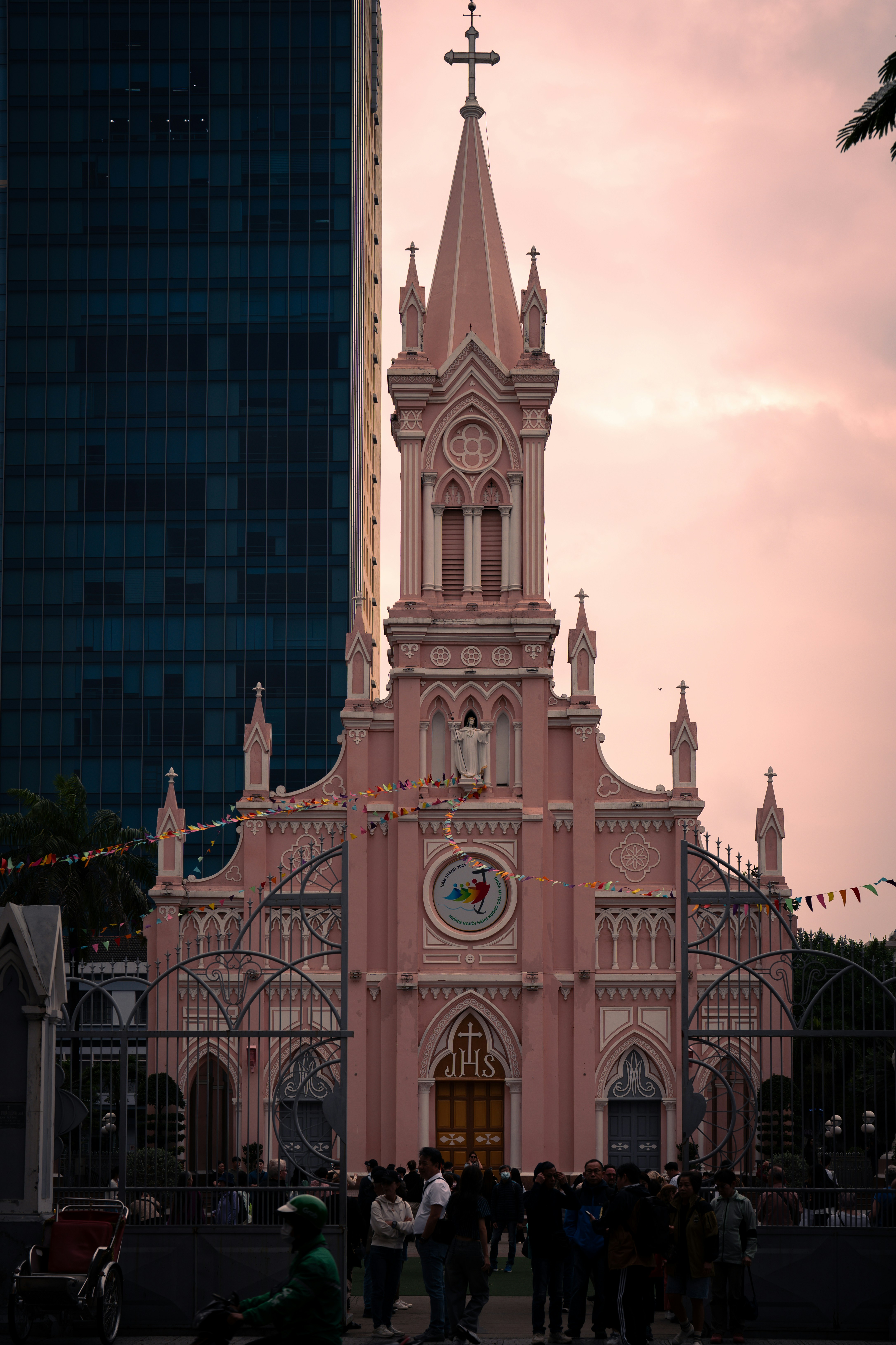 A pink church stands tall with a skyscraper behind.