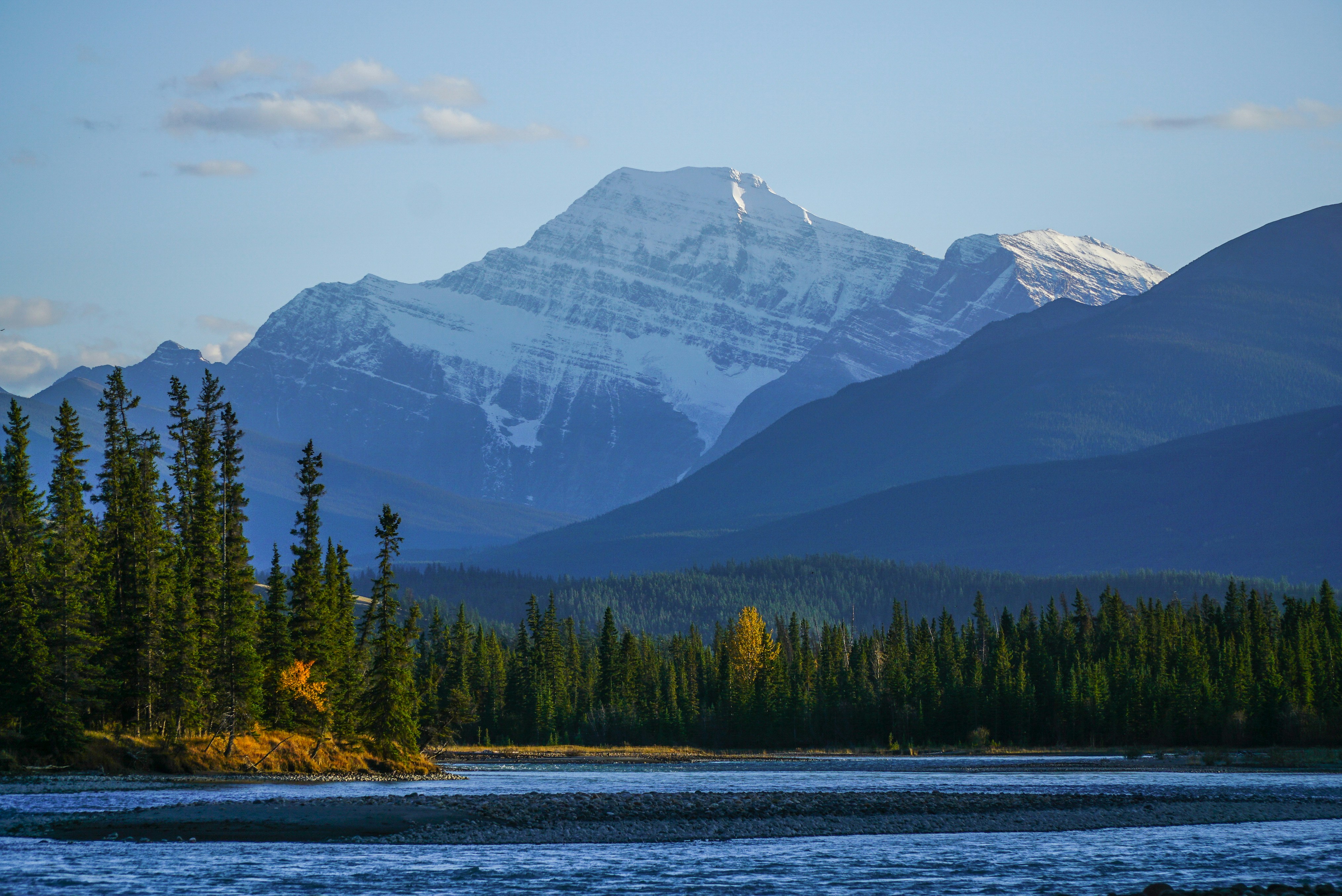Mountains rise above a calm river and forest. photo – Free Mountains ...