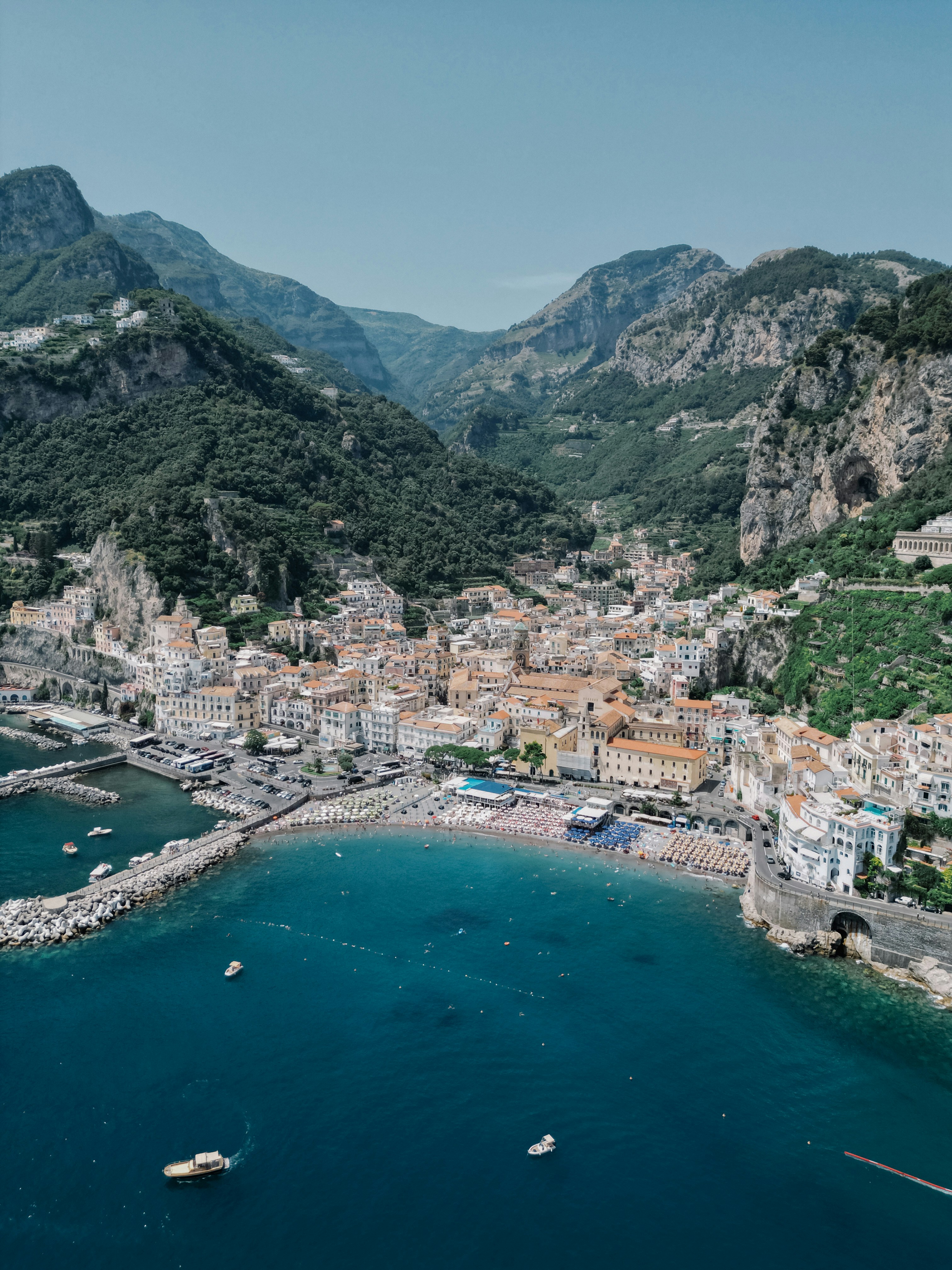 Aerial view of a coastal town nestled between lush mountains and a vibrant blue sea.