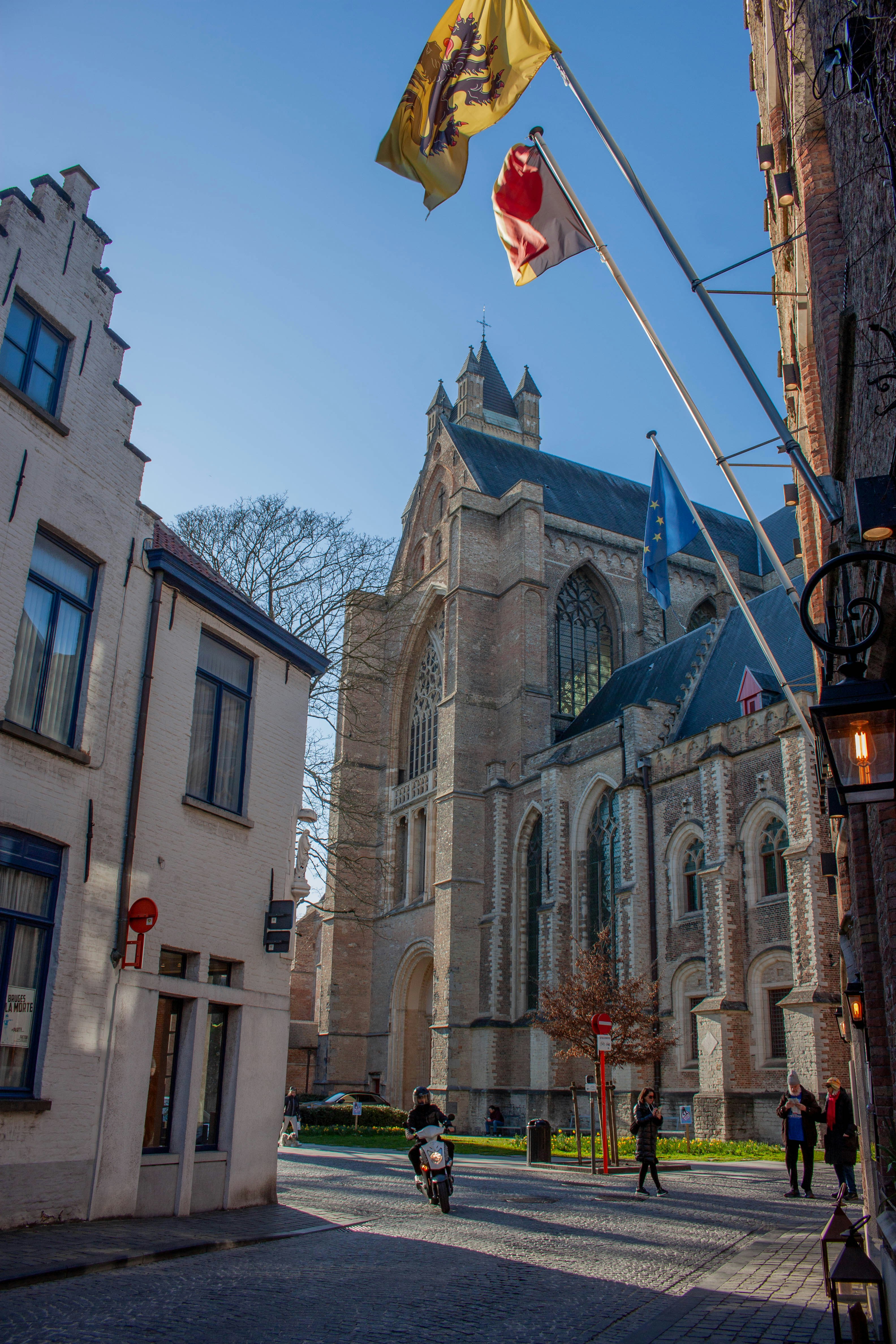 Flags Over the Gothic Street: A Sunlit Moment by the Cathedral
