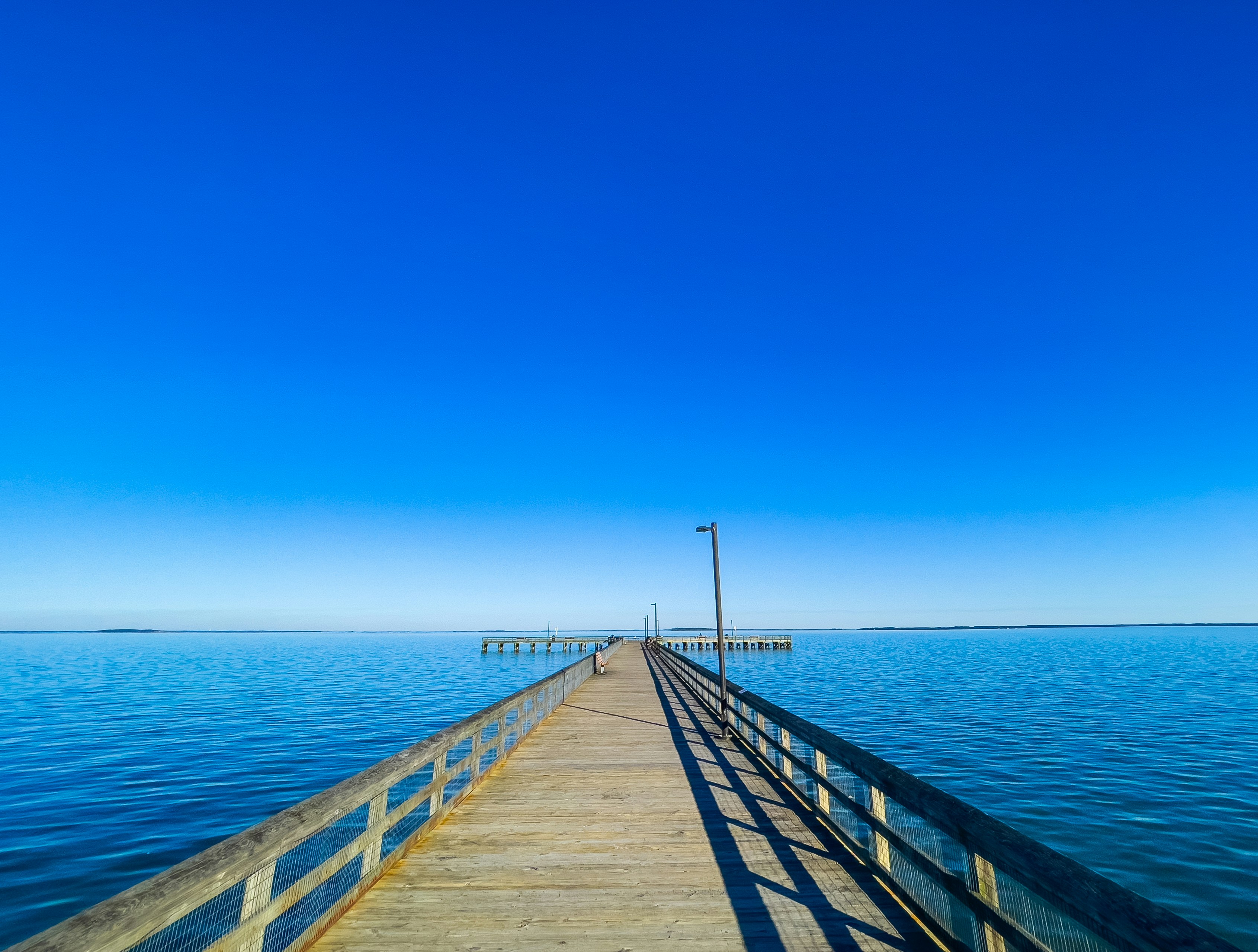 Muelle que se extiende hacia el océano azul y tranquilo. foto – Imagen ...
