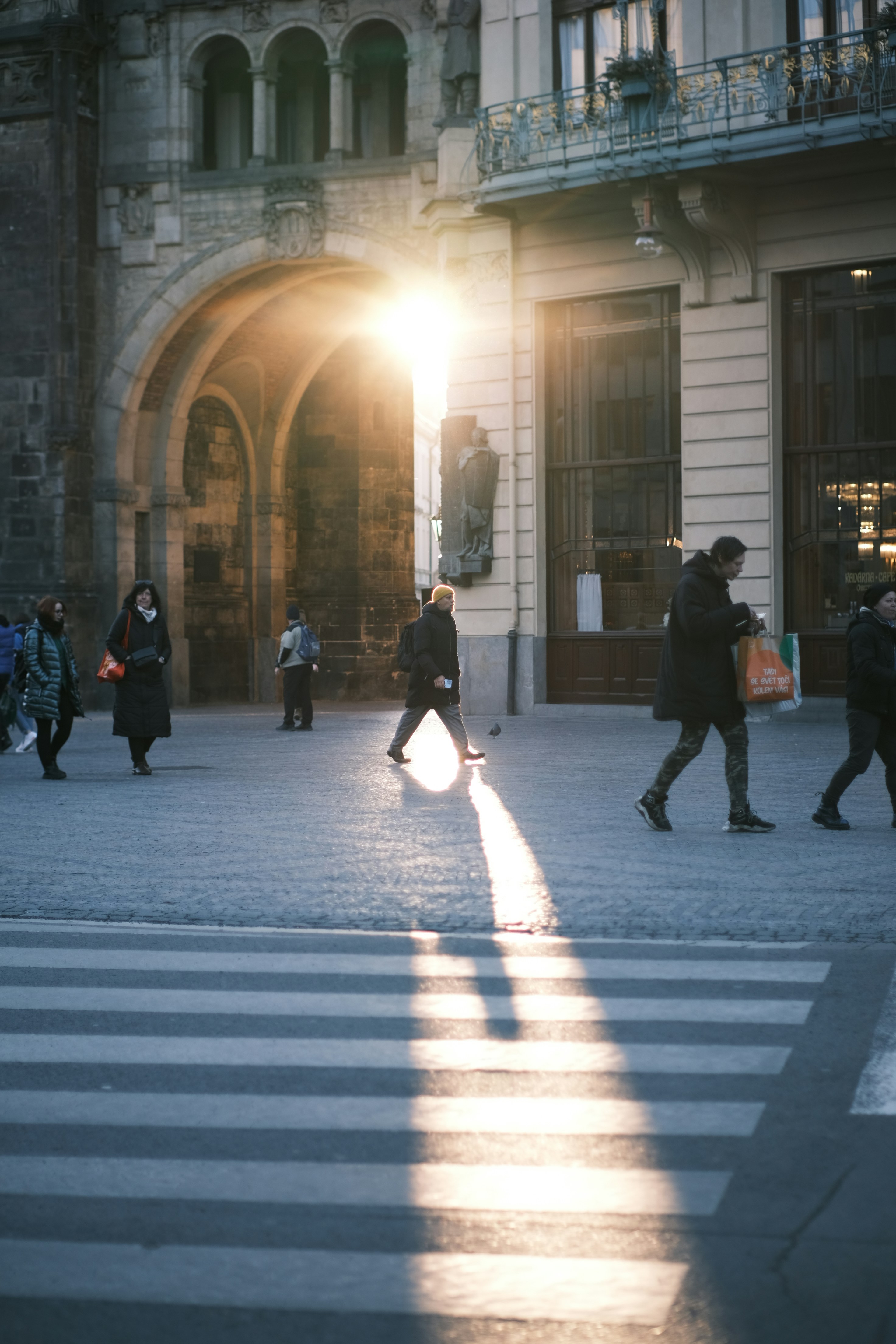 Sunlight Splits the Stone: Pedestrians Cross a Historic Arch at Golden Hour
