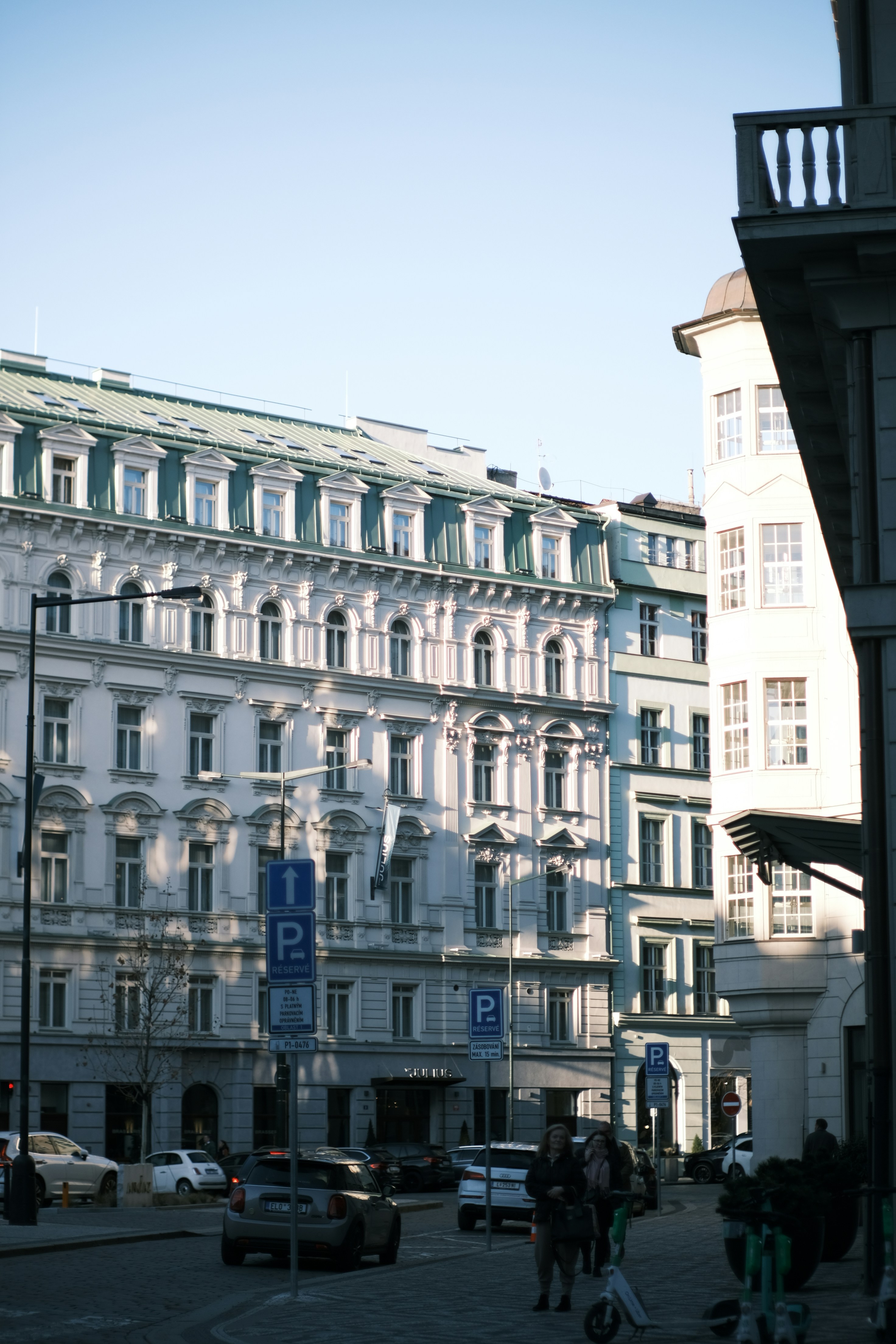 Elegant European architecture bathed in late afternoon sunlight, casting intricate shadows on a bustling city street.